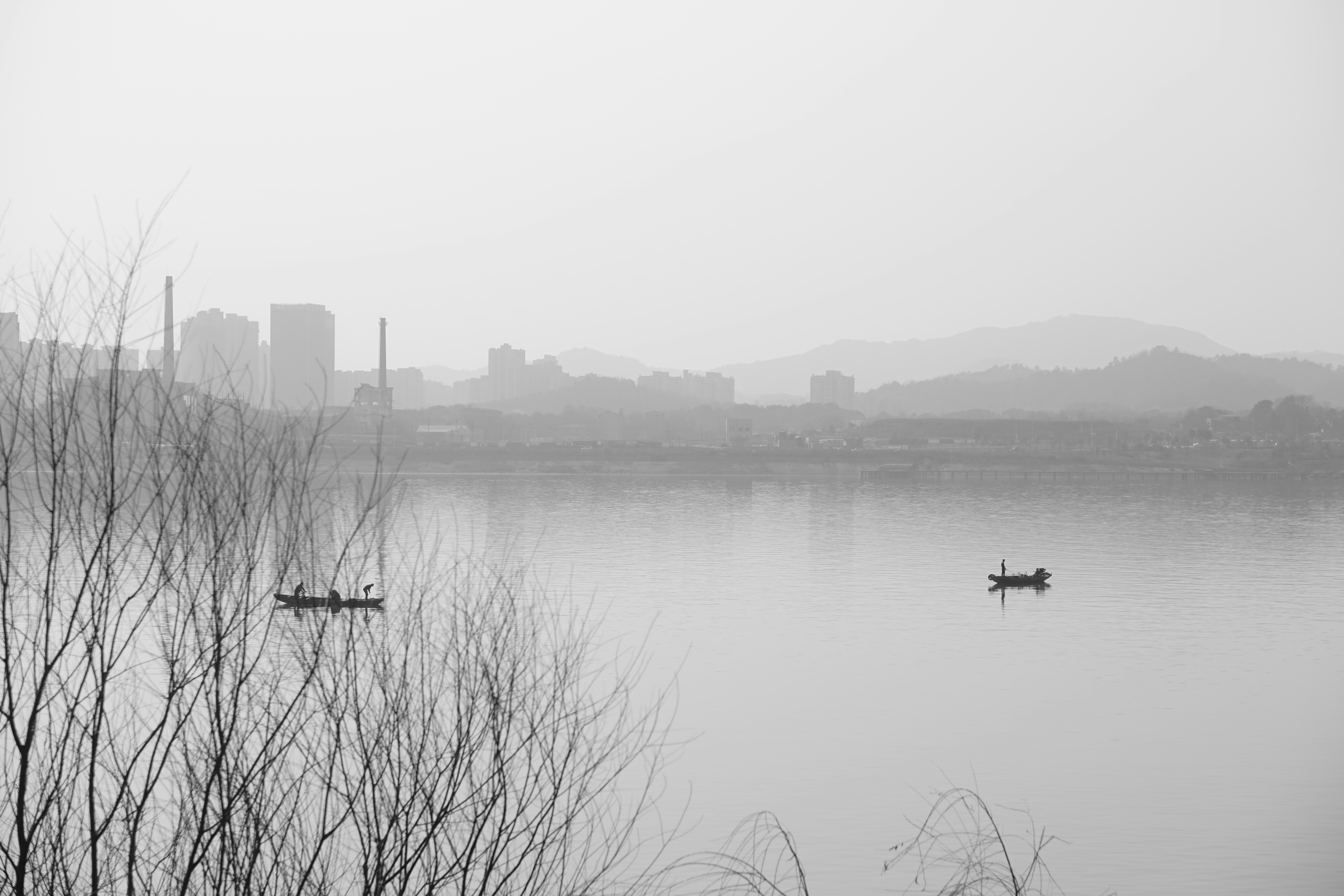 Lone Boat Drifting Beneath a Pale Industrial Horizon
