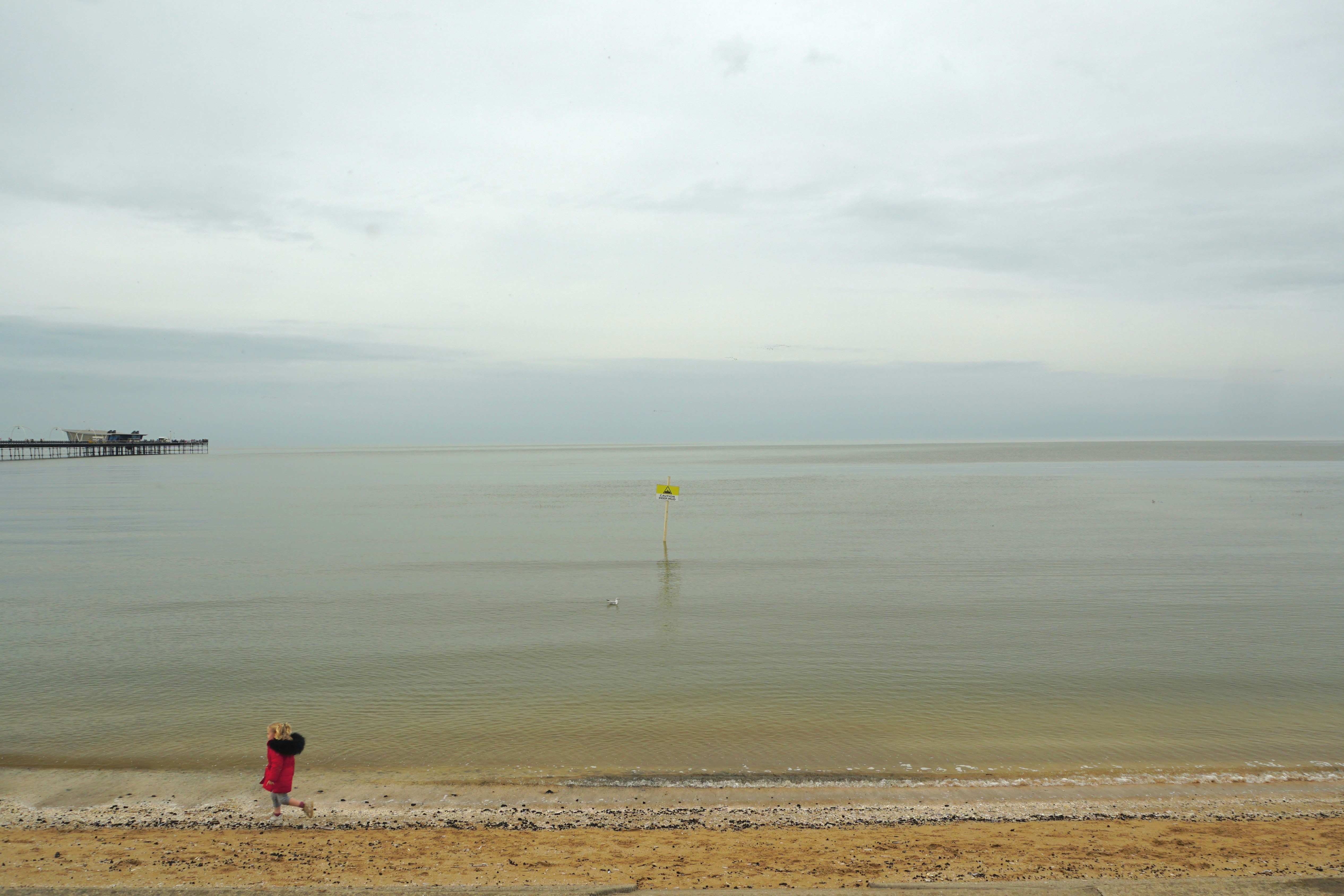 Red on the Shore: A Quiet Beach Scene with a Solitary Yellow Buoy