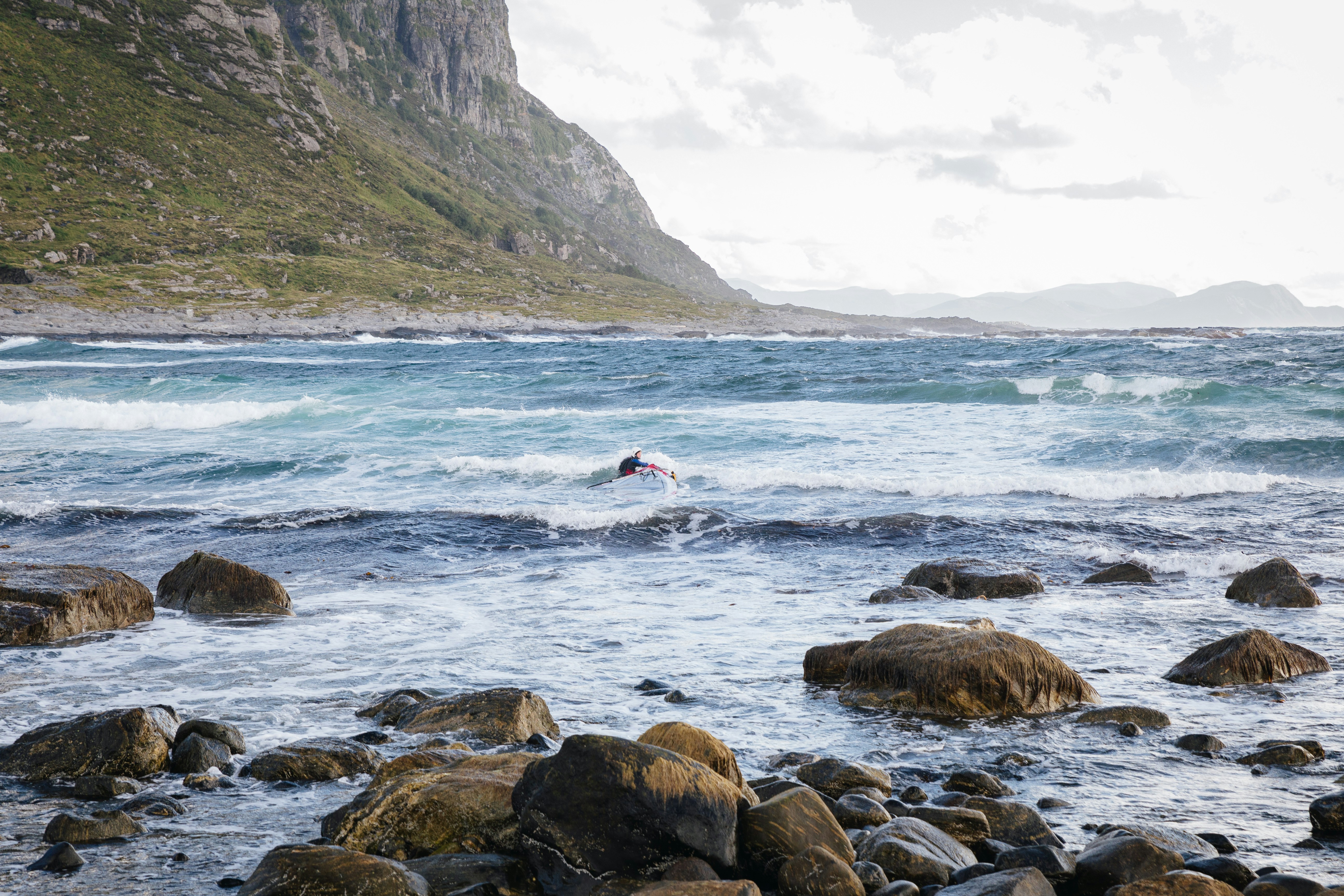 Edge of the Break: A Solitary Surfer Navigates a Wind-Swept Rocky Coast