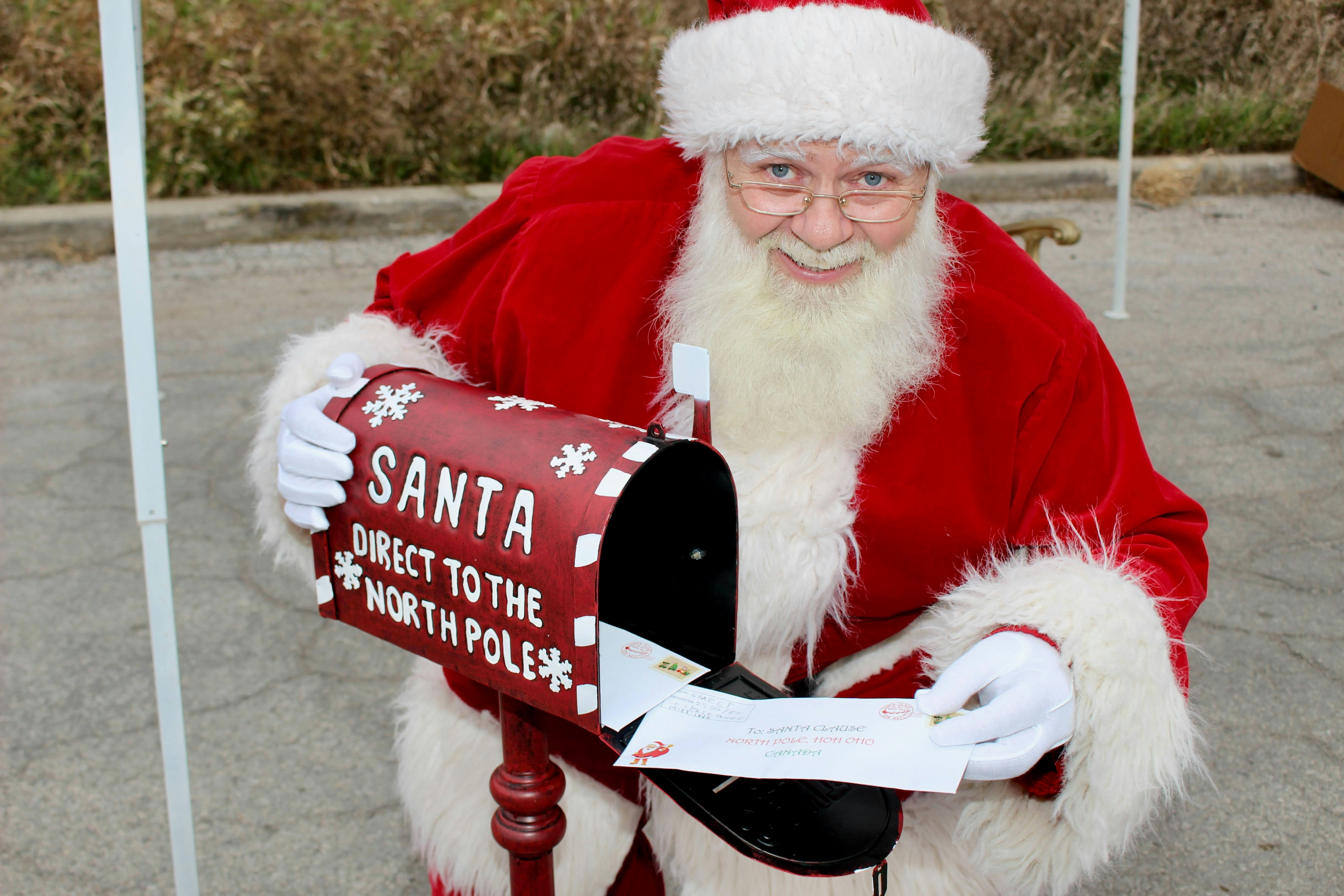 Jolly figure in a red suit, joyfully interacting with a festive mailbox labeled 'SANTA DIRECT TO THE NORTH POLE'.
