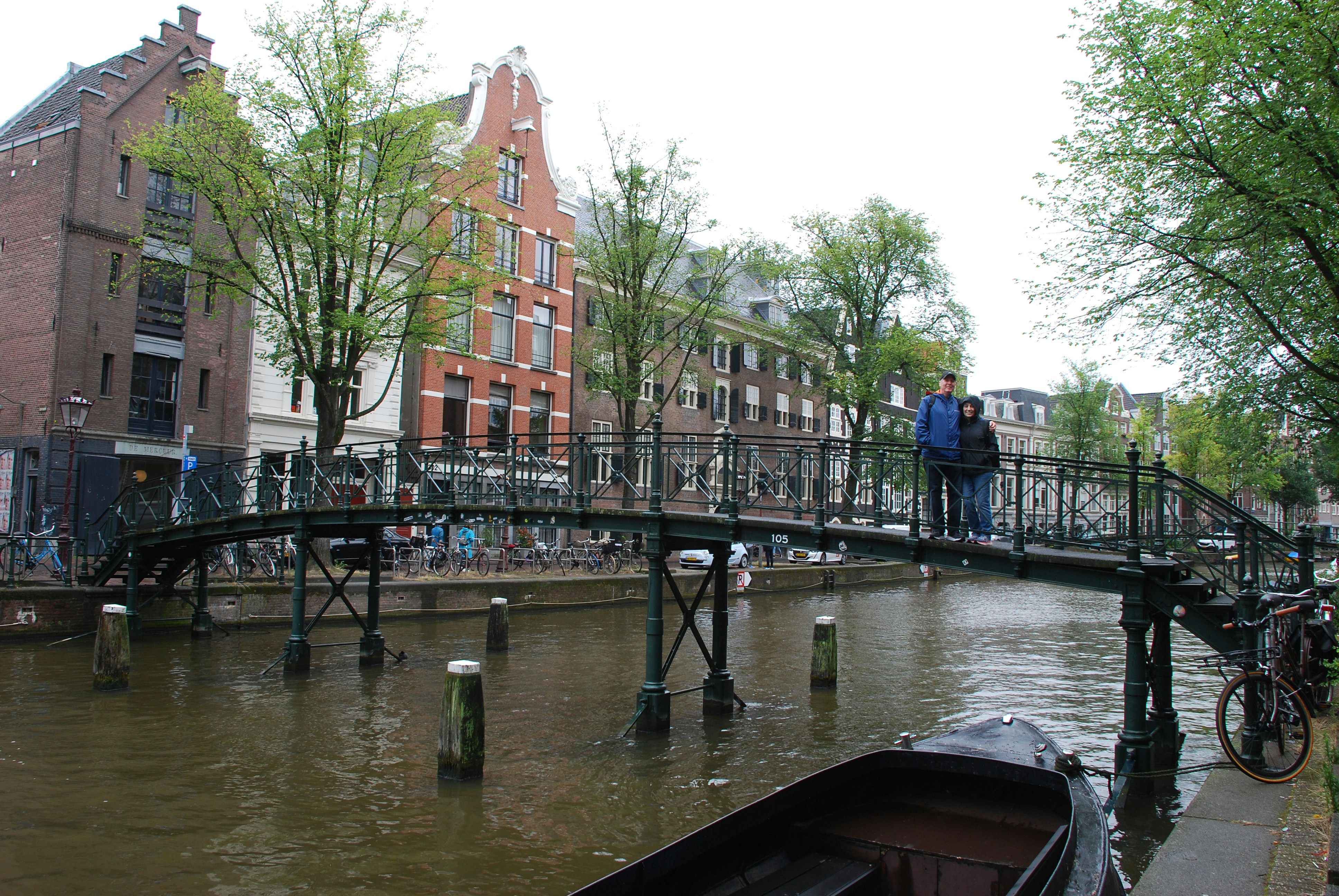 Bridge-side Moment: Pedestrians Pause on a Canal Bridge Amid Brick Townhouses