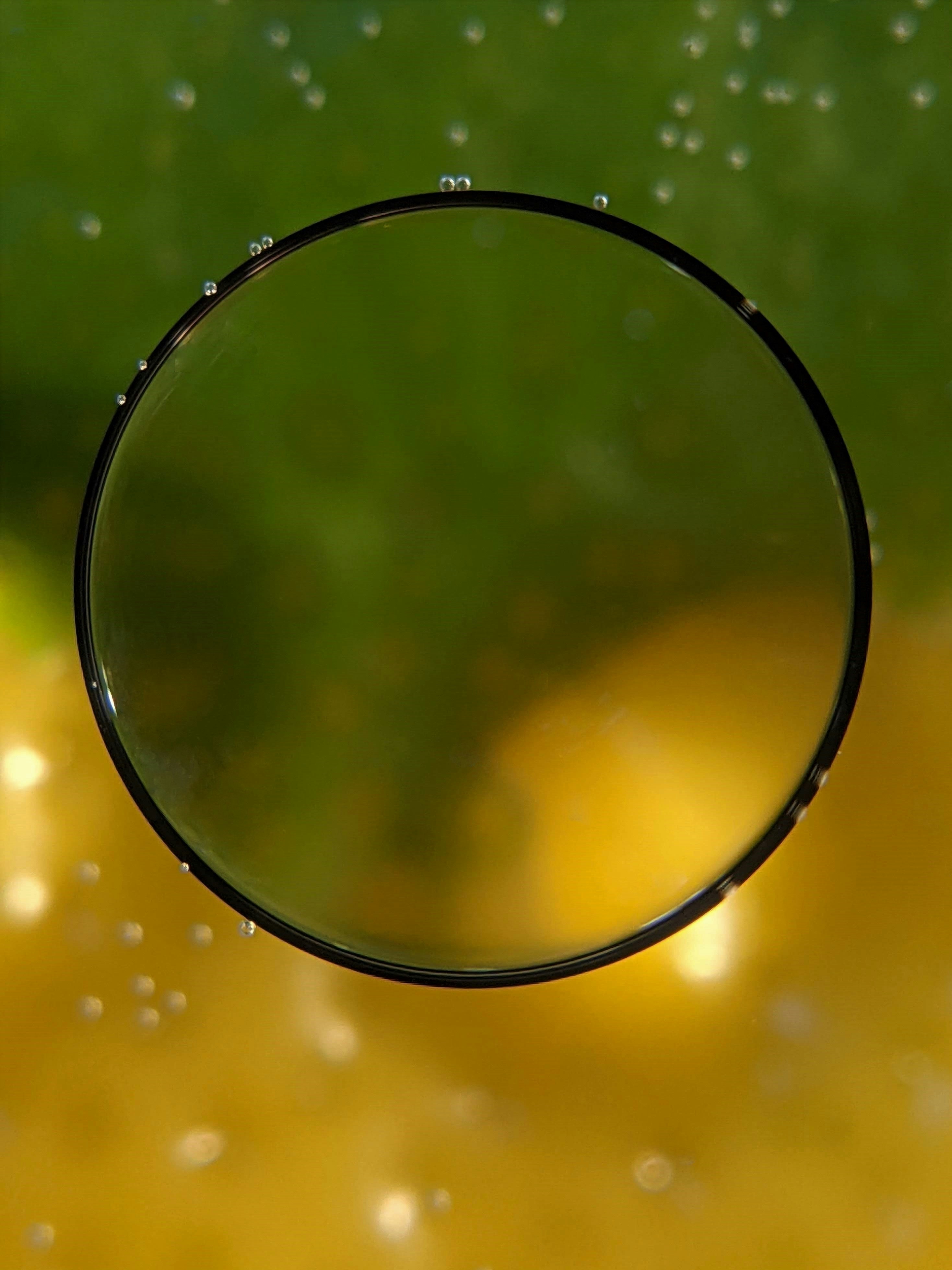 Circular Ring in Glass: A Macro Study of Dew-Dotted Edges against a Warm Bokeh