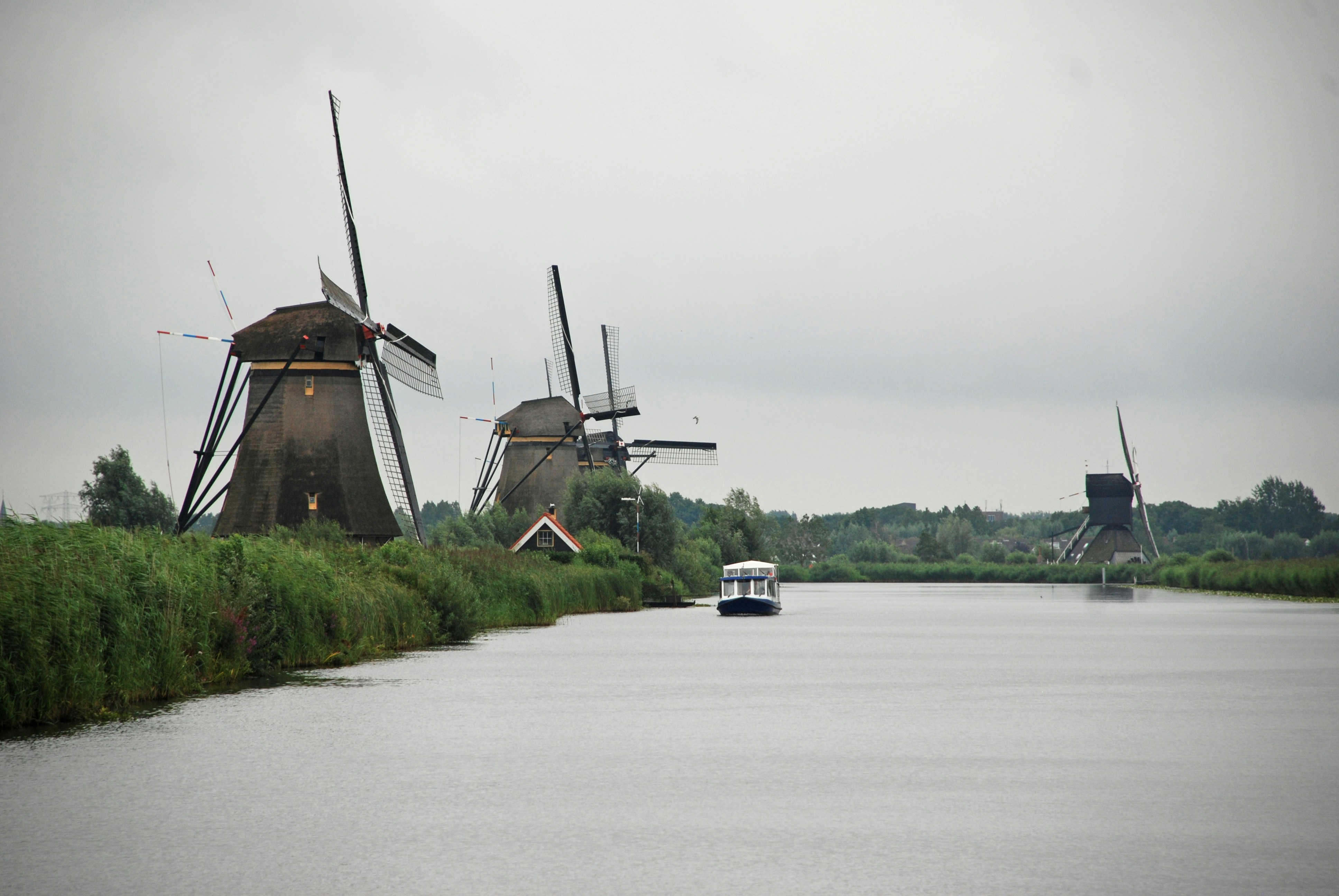 A boat traveling down a river next to windmills photo – Free Kinderdijk Image on Unsplash