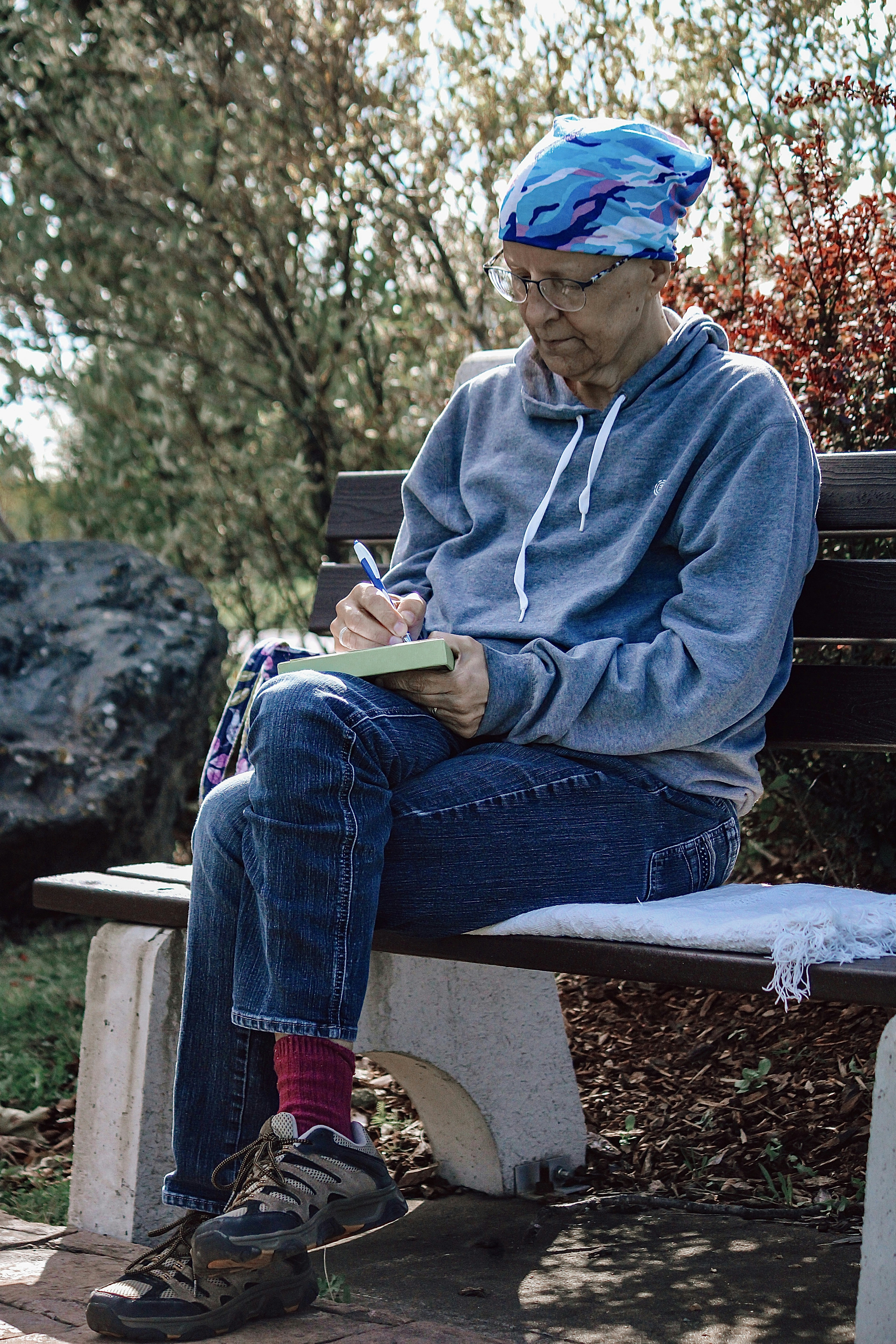 a person sitting on a bench writing on a piece of paper