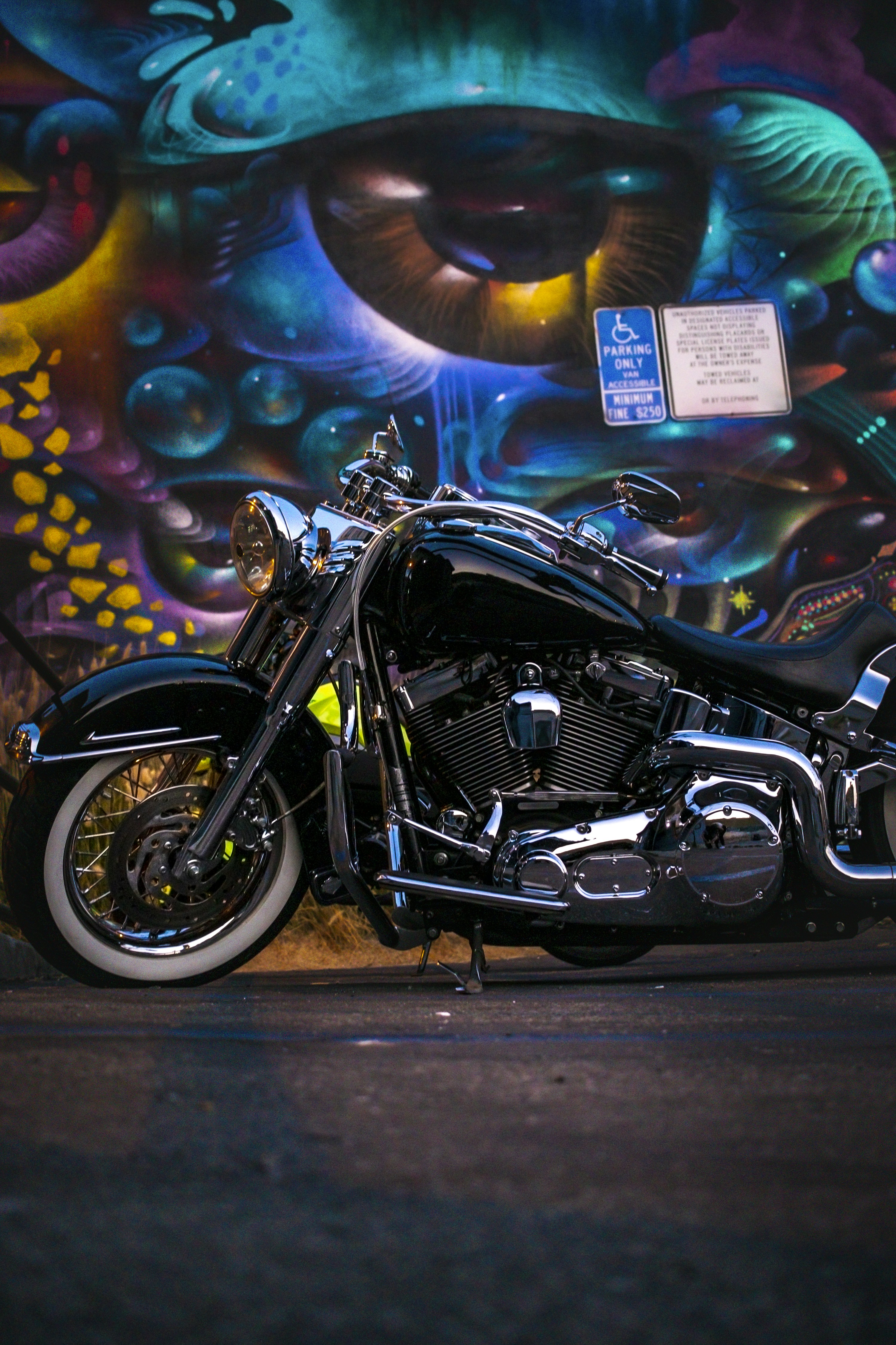 Classic motorcycle parked beside a vibrant street mural, showcasing intricate designs and vivid colors.