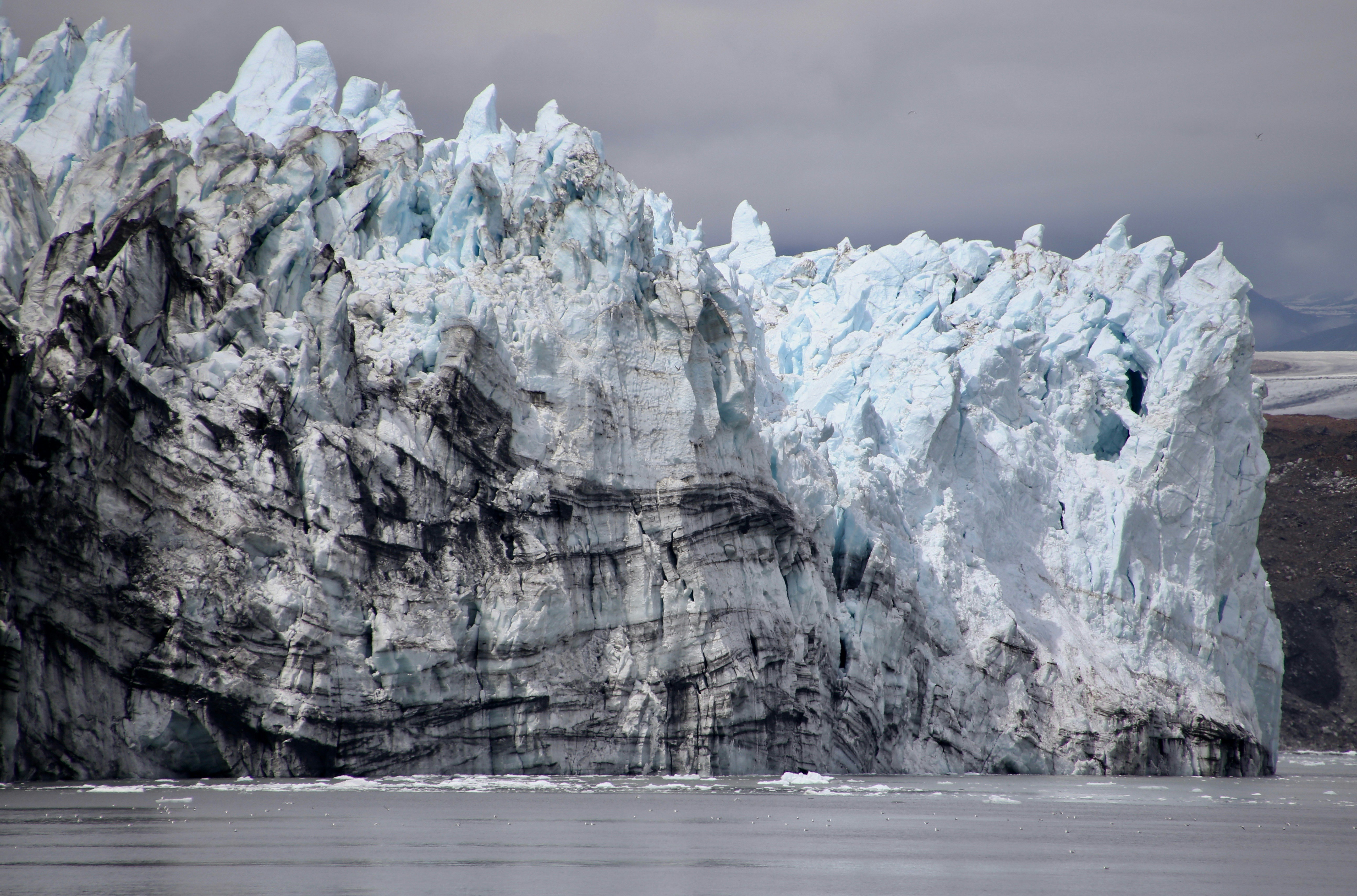 A large iceberg towering over a body of water photo – Free Ice Image on ...
