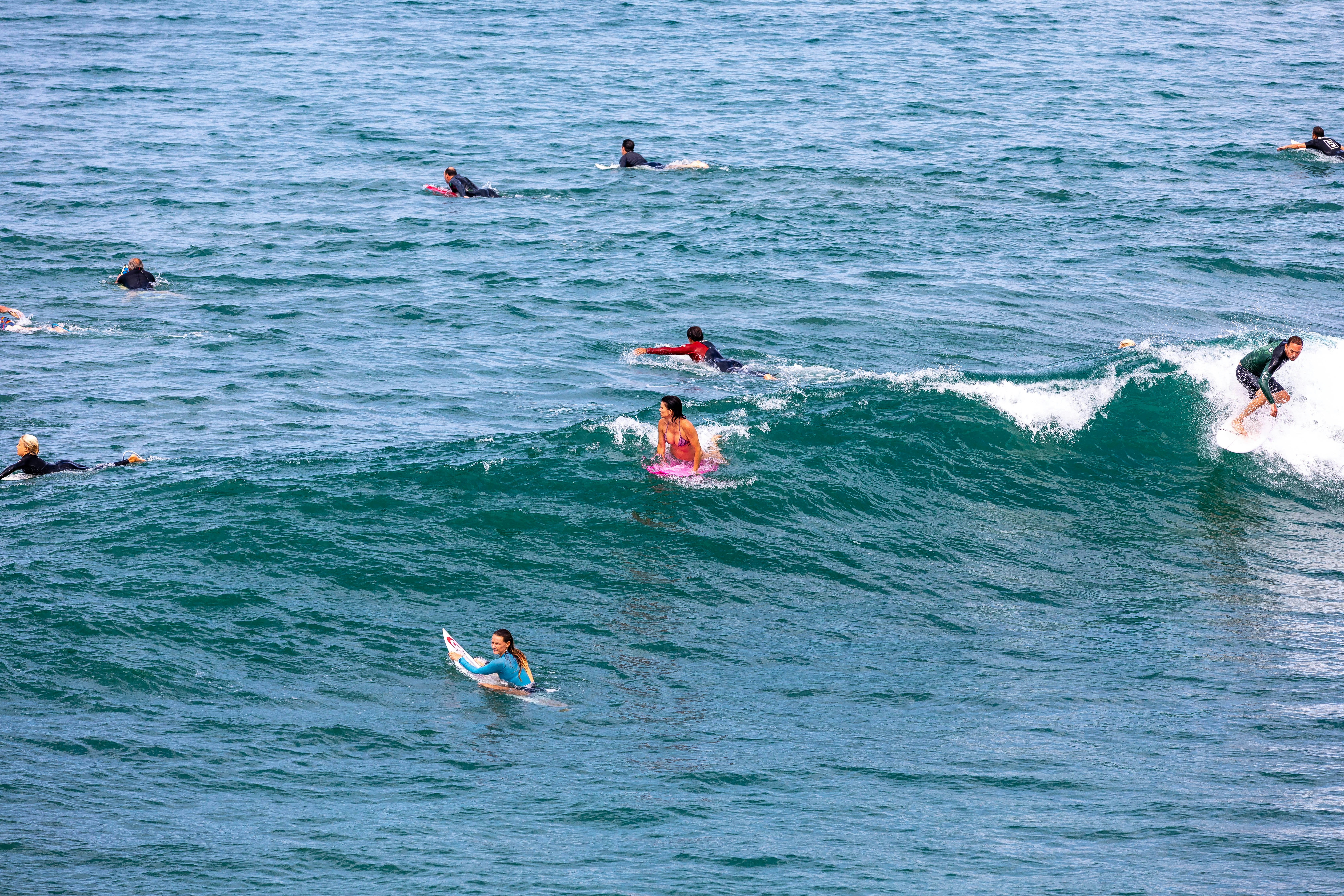 A group of people riding surfboards on top of a wave photo – Free Ocean ...