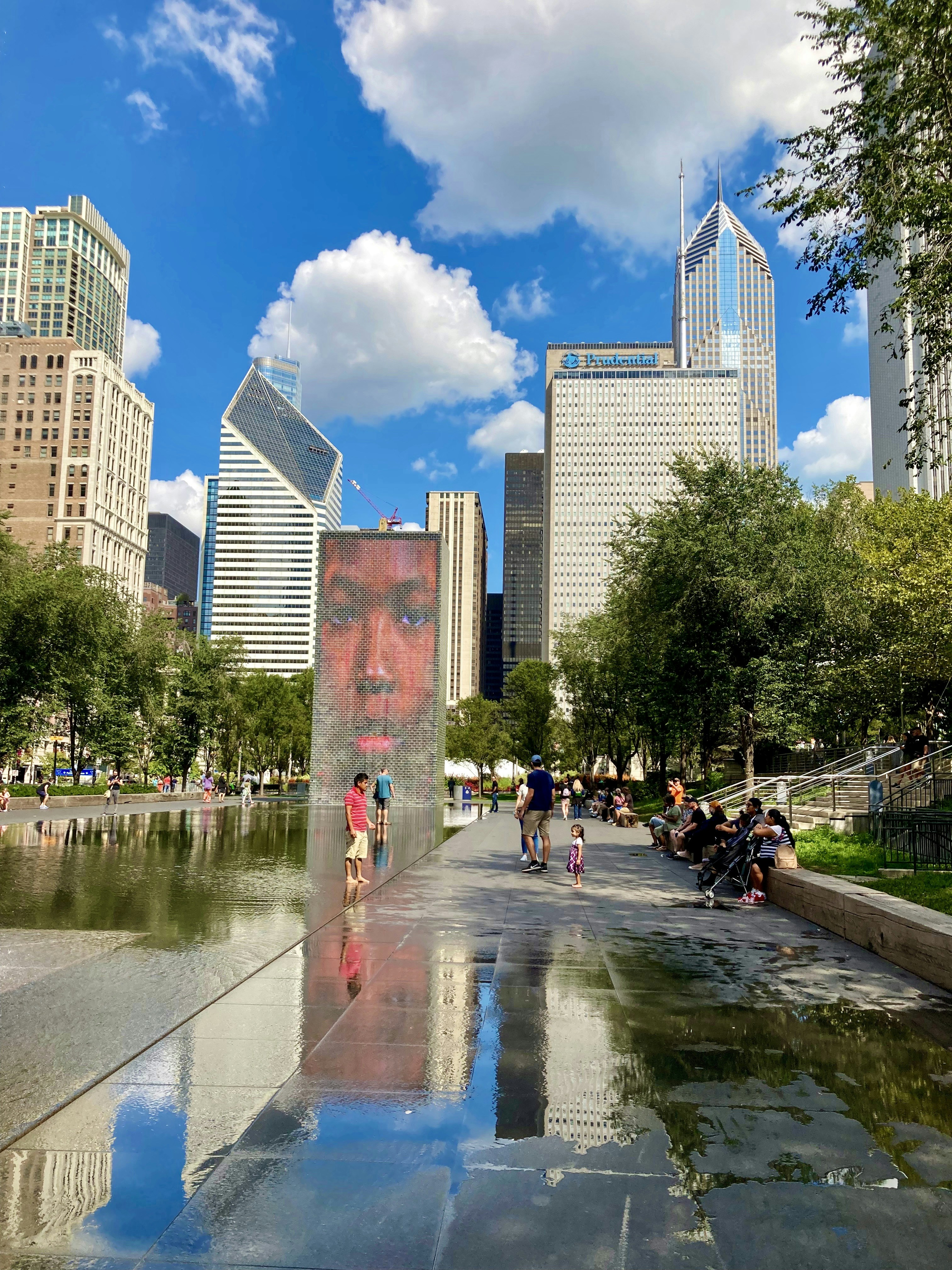 A vibrant digital fountain display juxtaposed against a city skyline, with visitors enjoying the serene atmosphere. The scene captures both nature and urban life harmoniously.