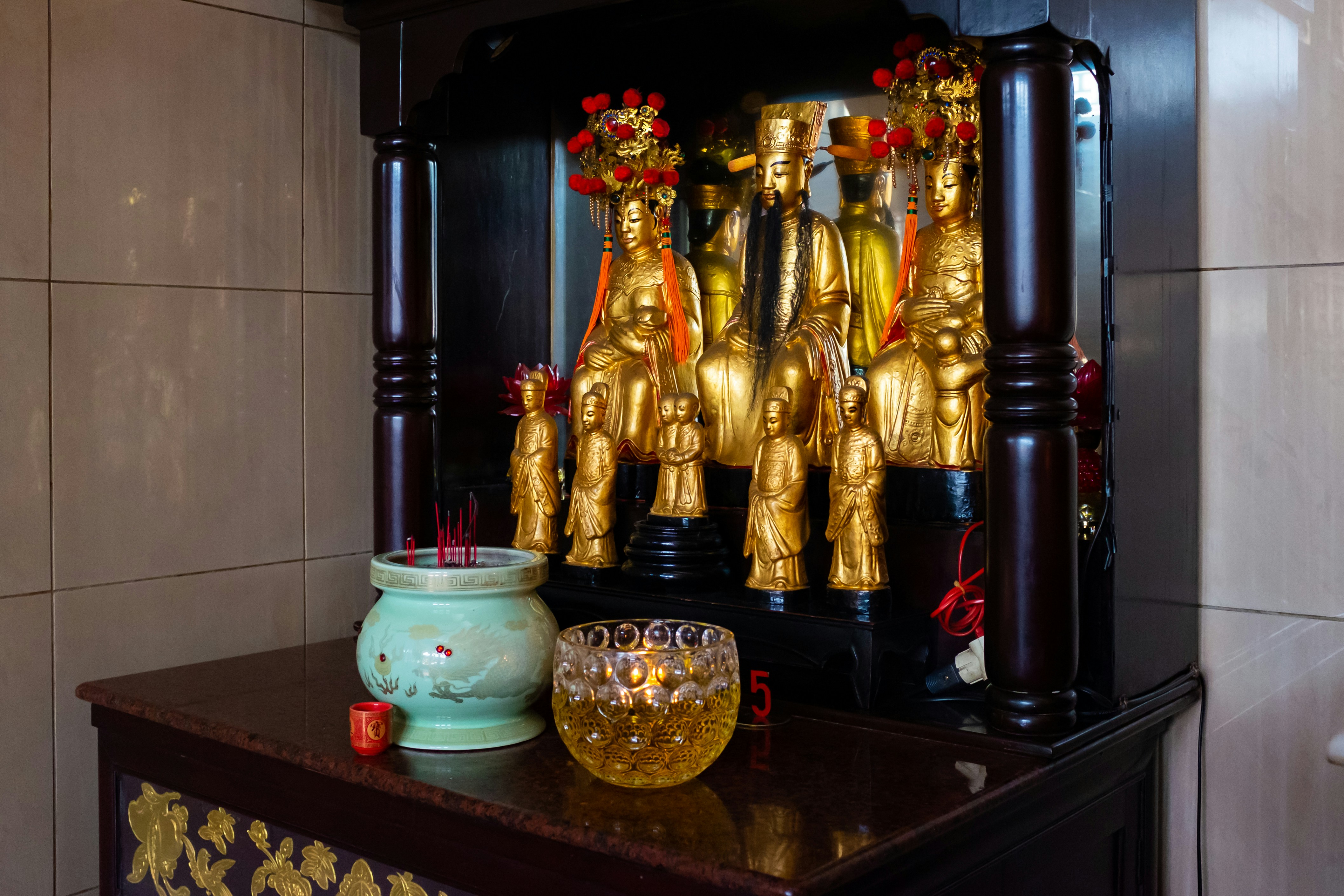 A small shrine with gold statues and a glass bowl photo – Free Jakarta ...