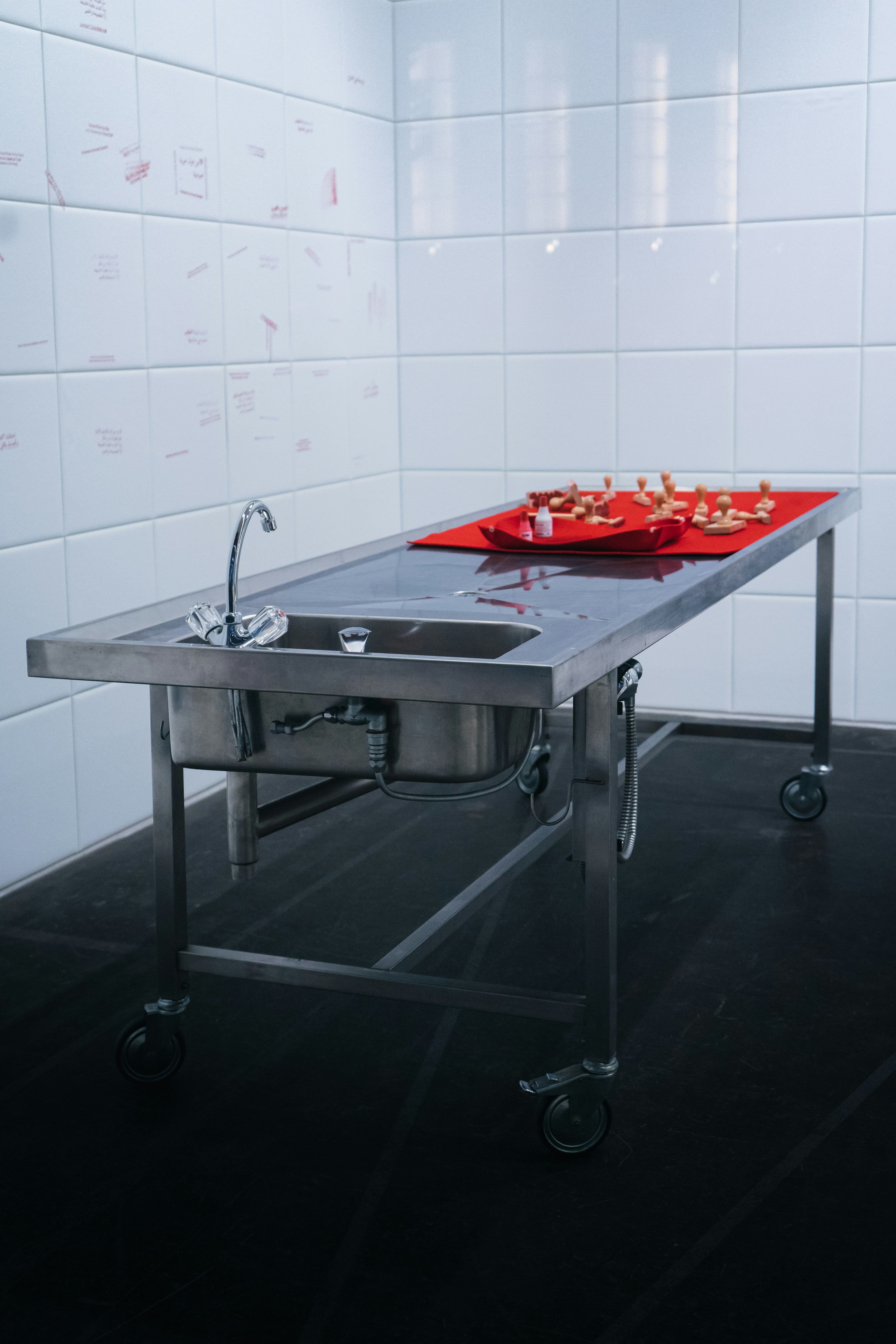 Crimson Board of Tiny Figures on a Stainless Prep Table