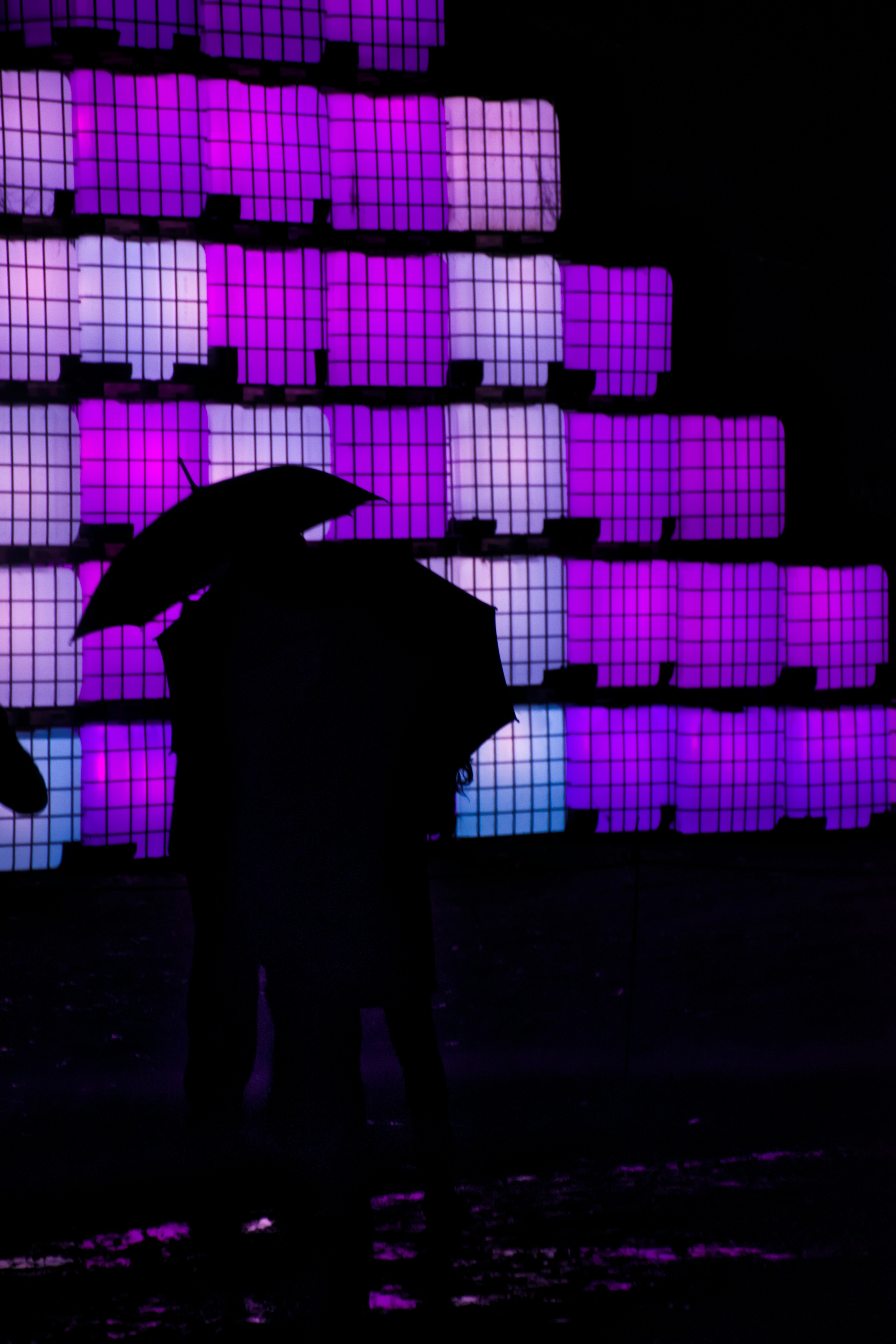 Neon-Grid Embrace: Umbrella Silhouettes Beneath a Pulsing Purple Skyline