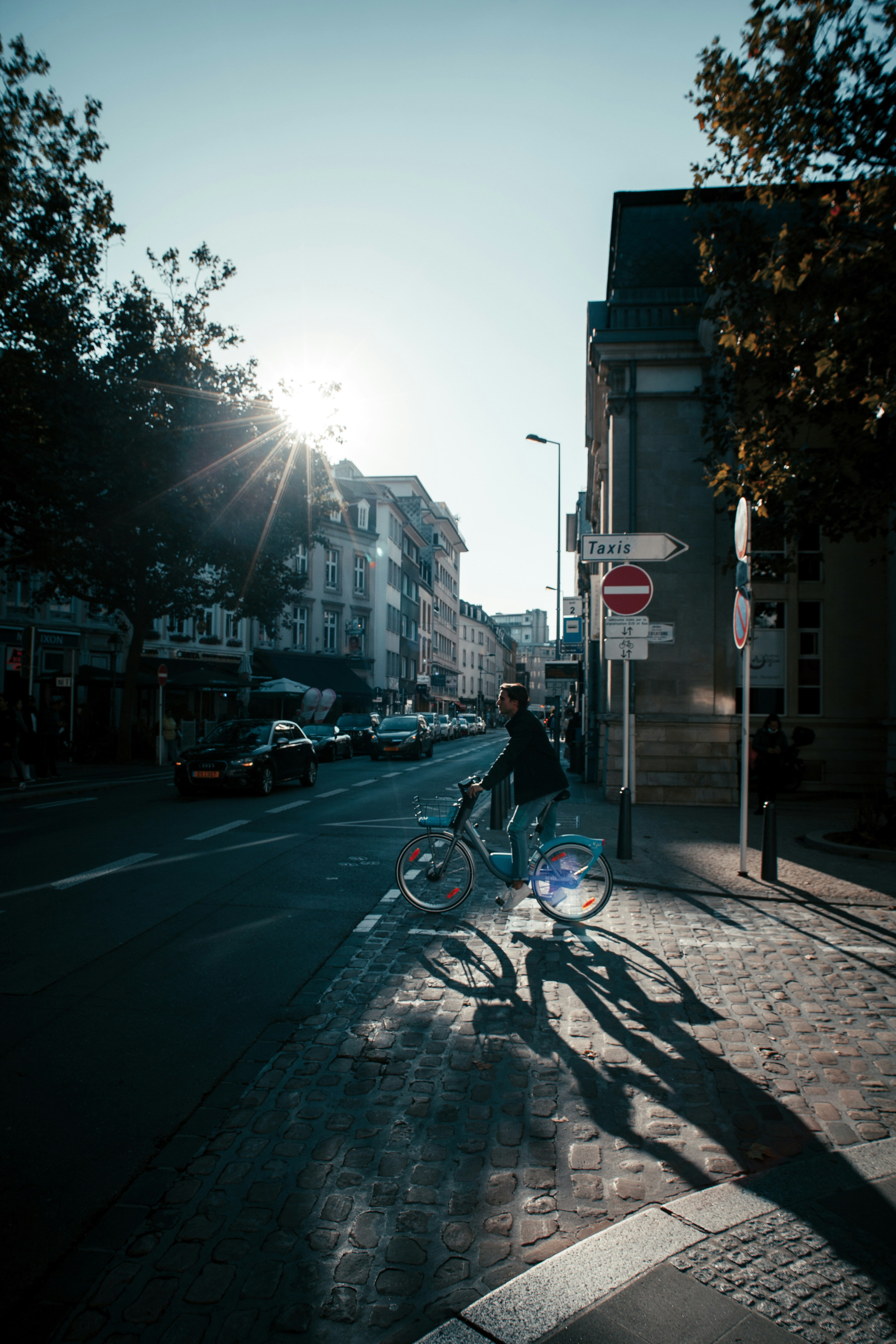 A man riding a bike down a street next to tall buildings photo – Free ...