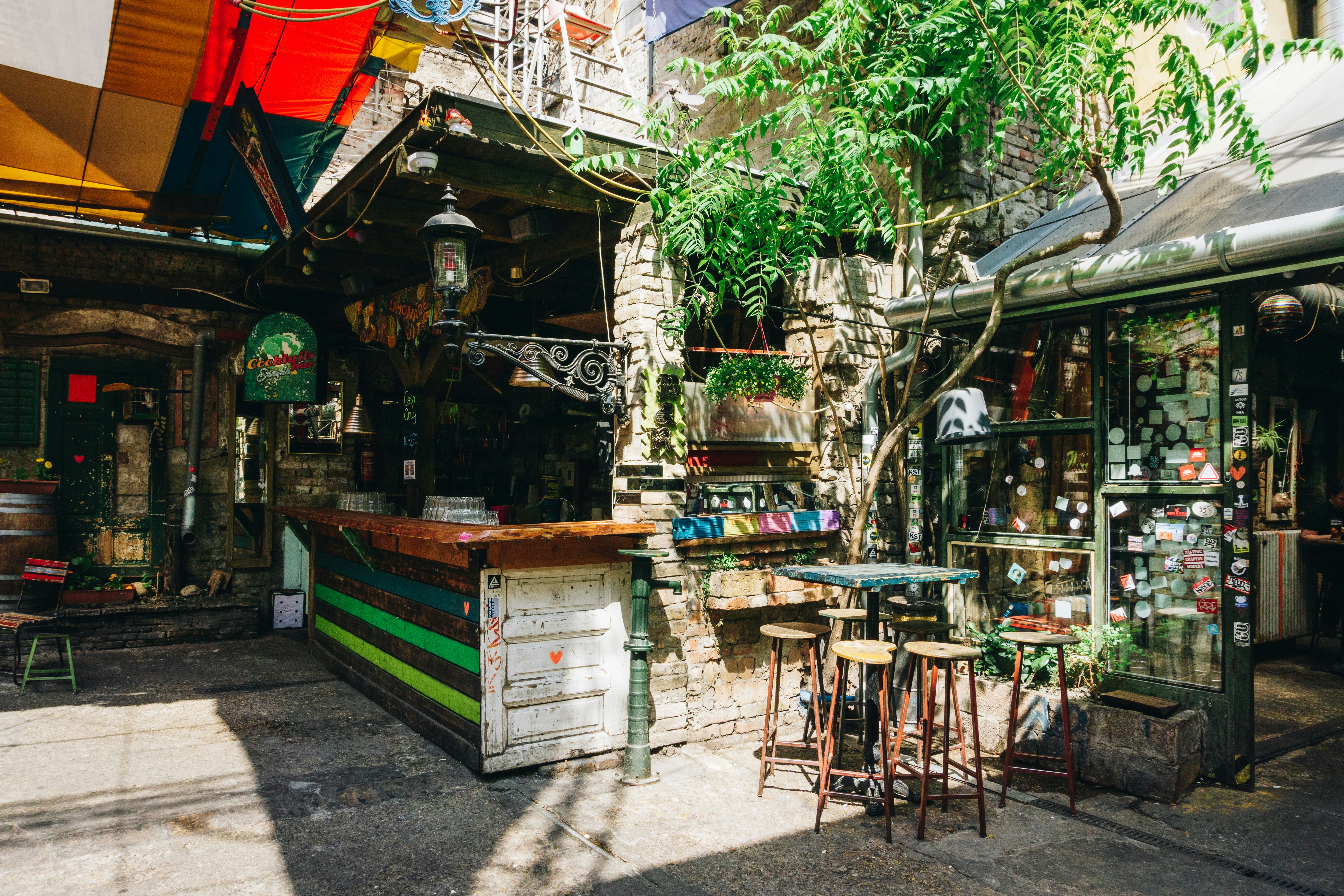 An outdoor cafe with tables and stools in front of it photo – Free ...
