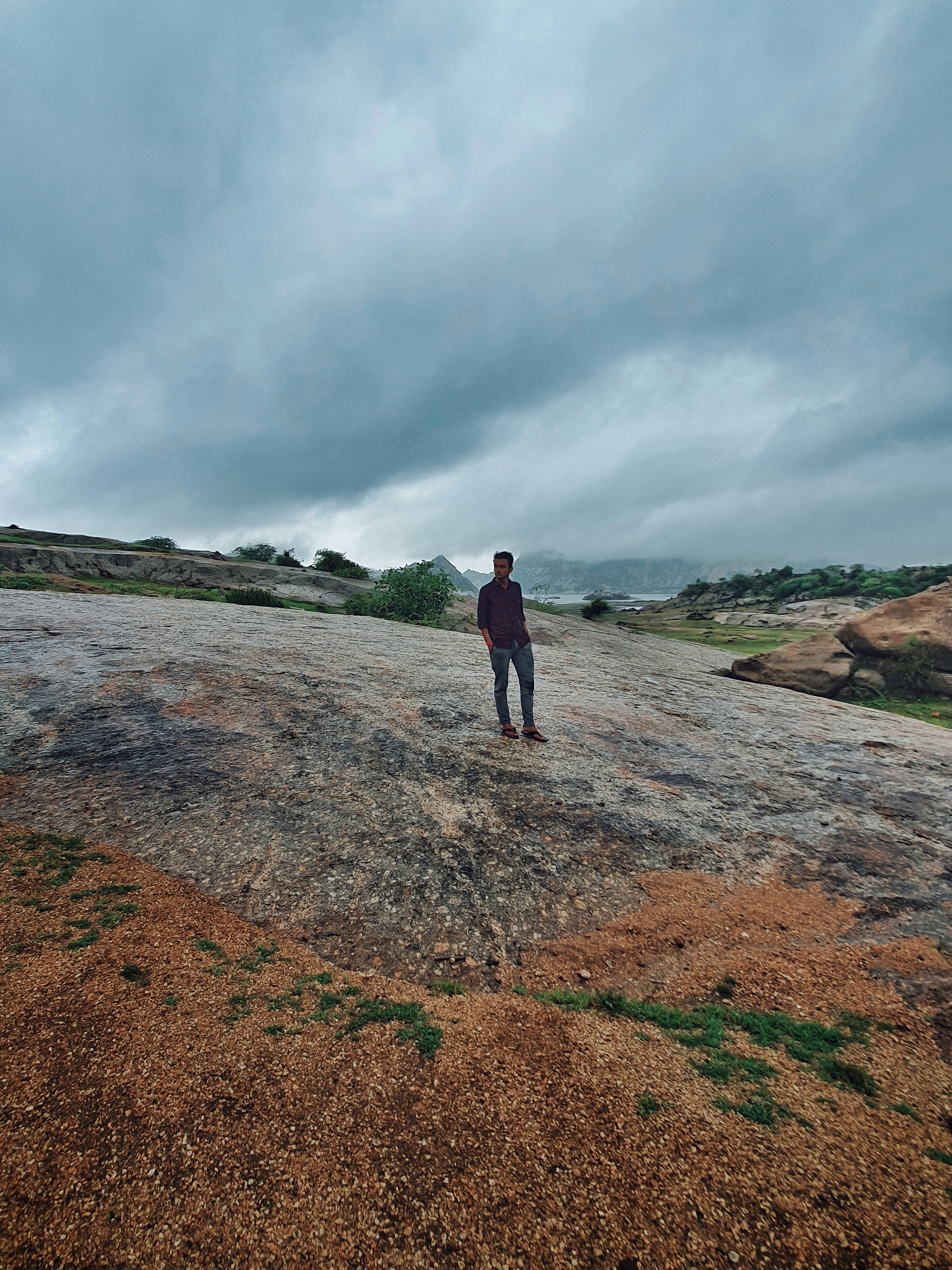 Lone wanderer on weathered granite under a brooding sky