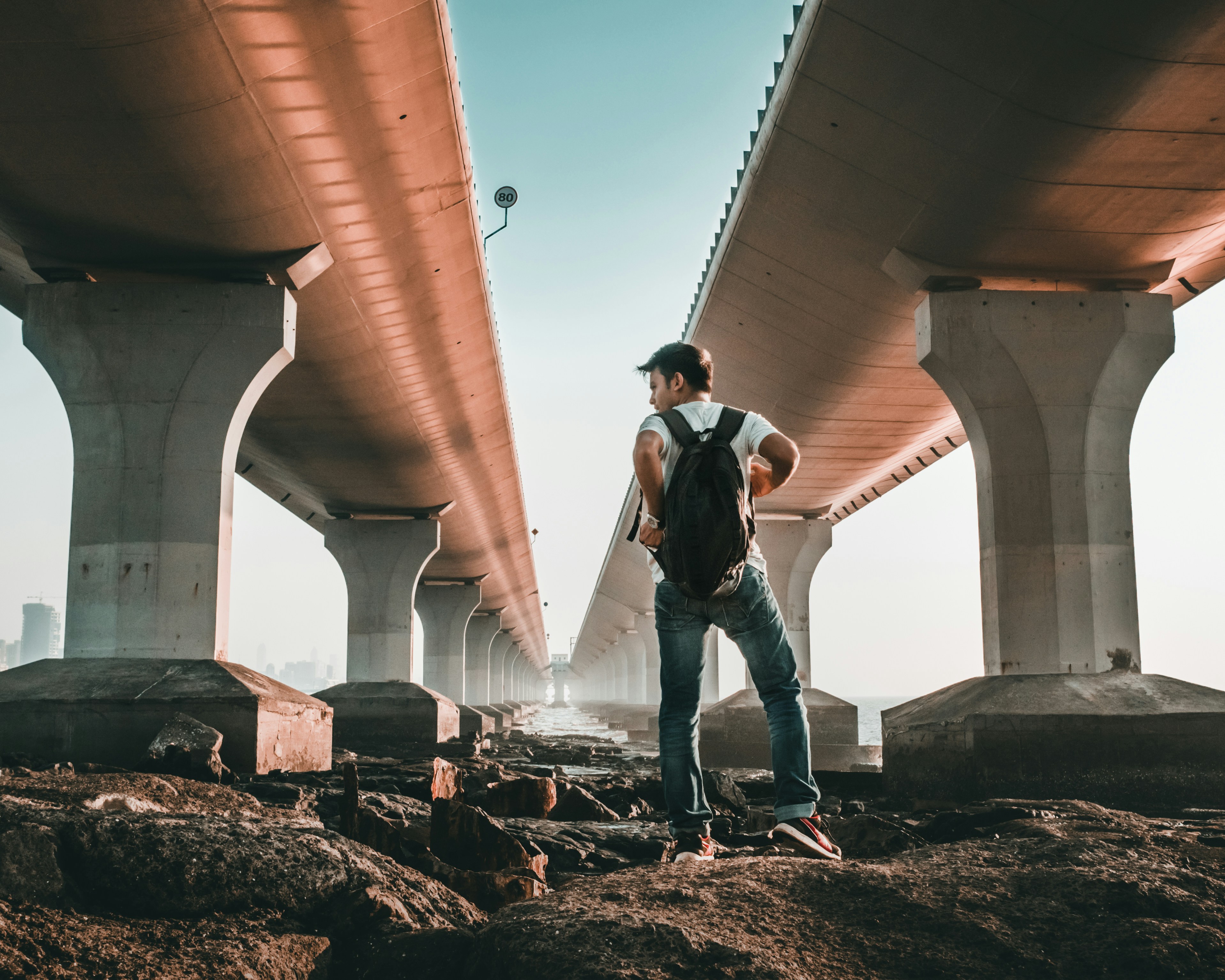 Between Concrete Giants: A Lone Hiker in a Pillared Canyon