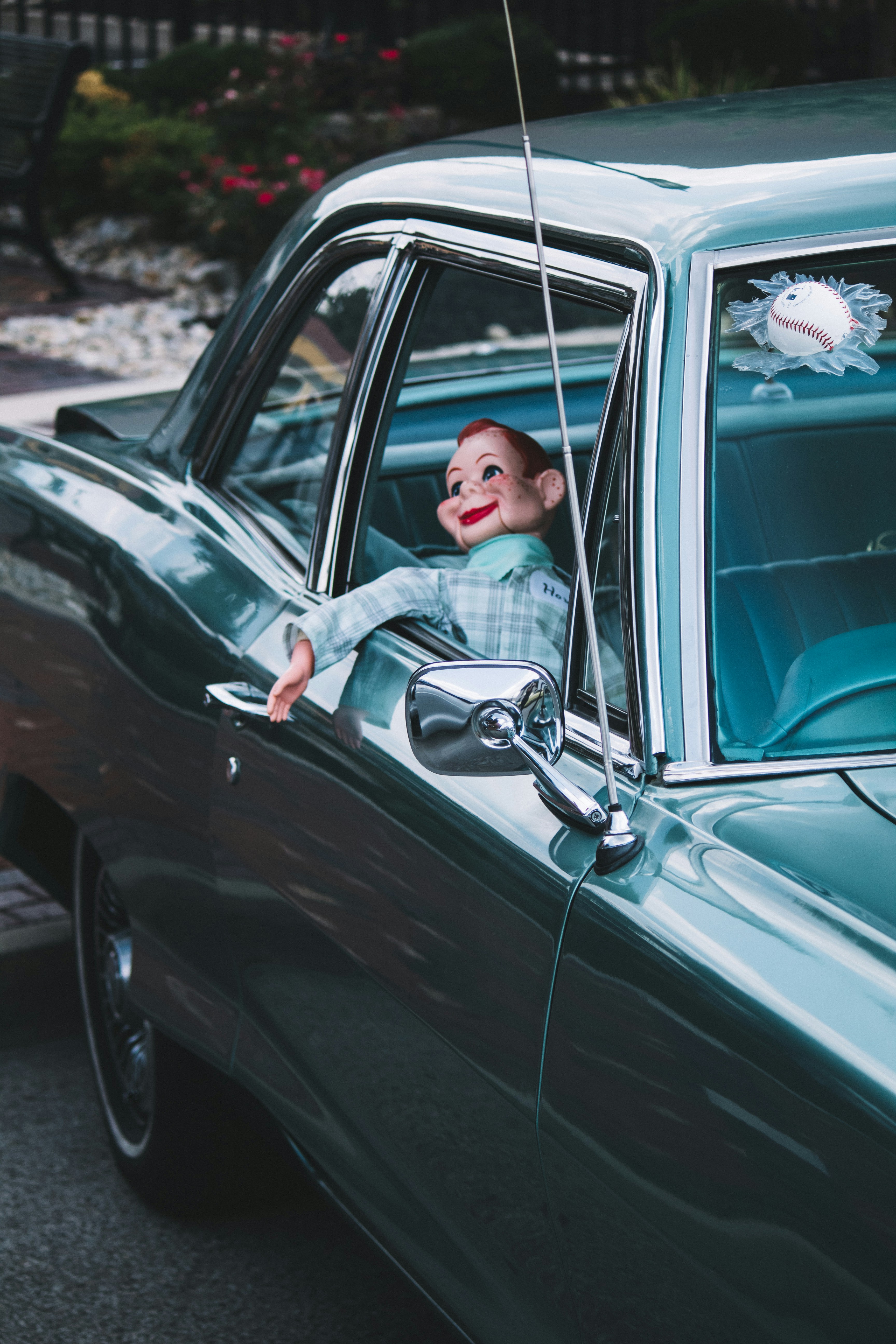 Vintage car with a puppet cheerfully sitting in the driver's seat, showcasing a blend of classic automotive charm and whimsical character.