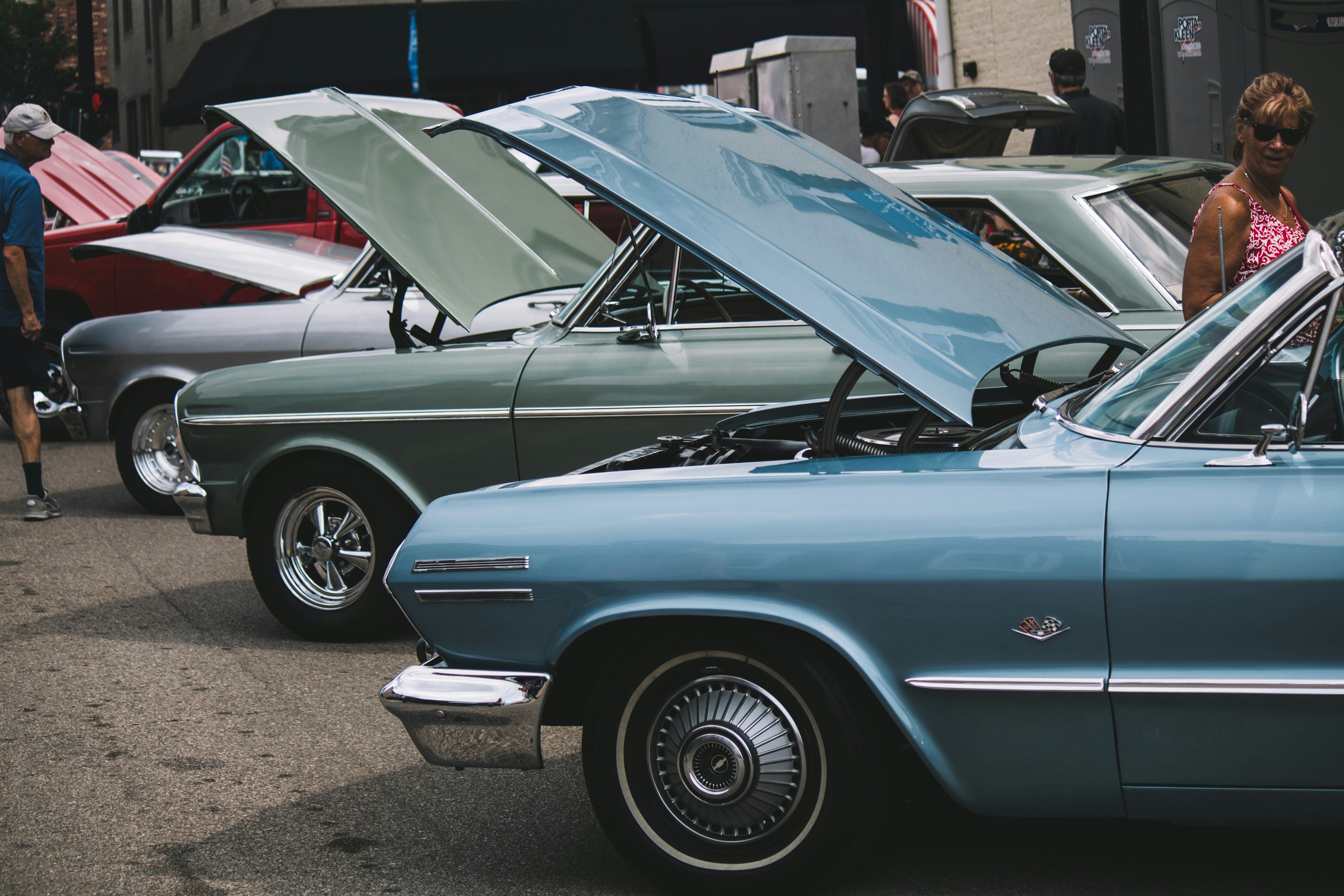 A woman standing next to a car with its hood open photo – Free Street ...