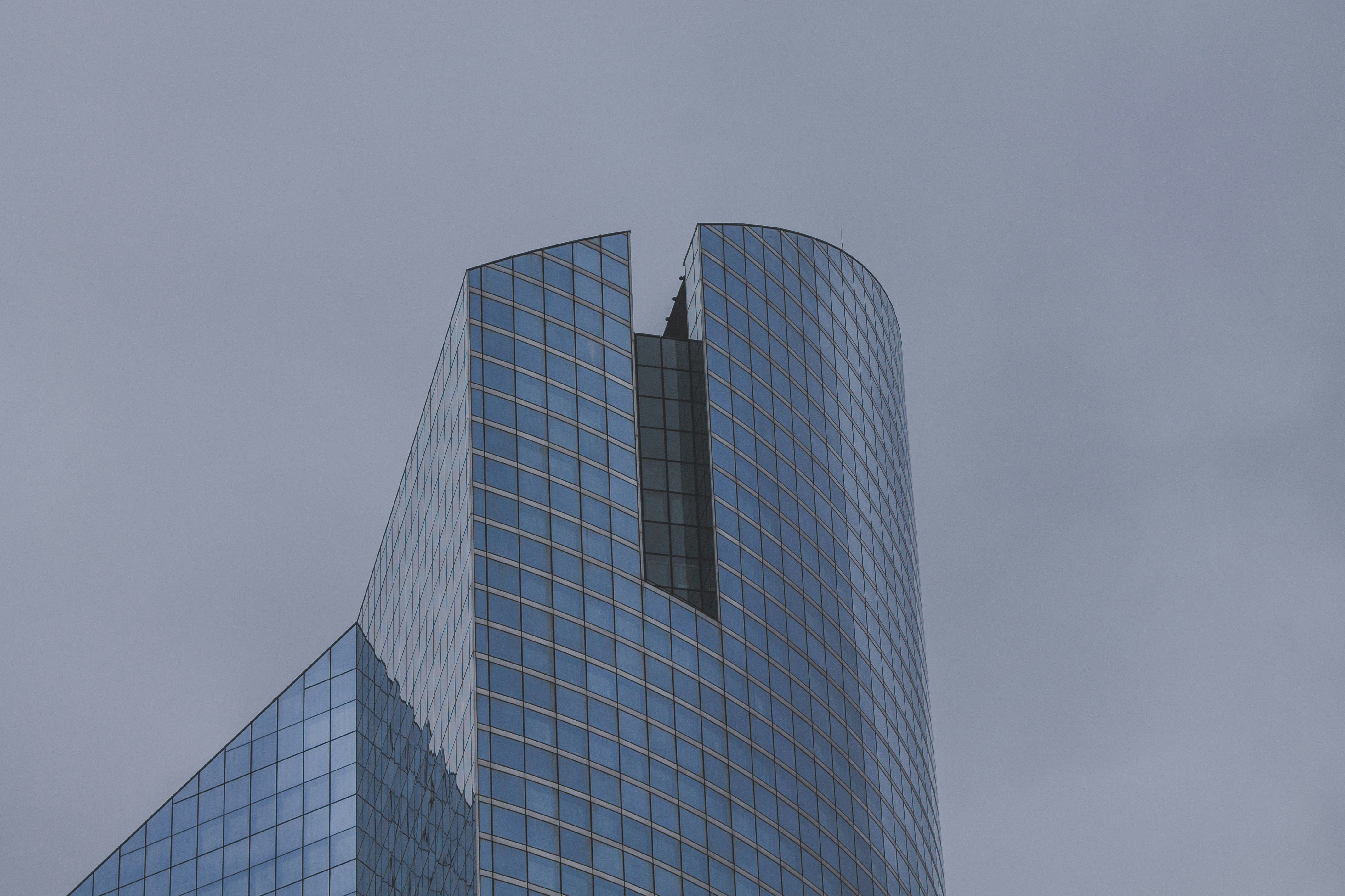 A very tall glass building with a clock on it's side photo – Free Grey ...