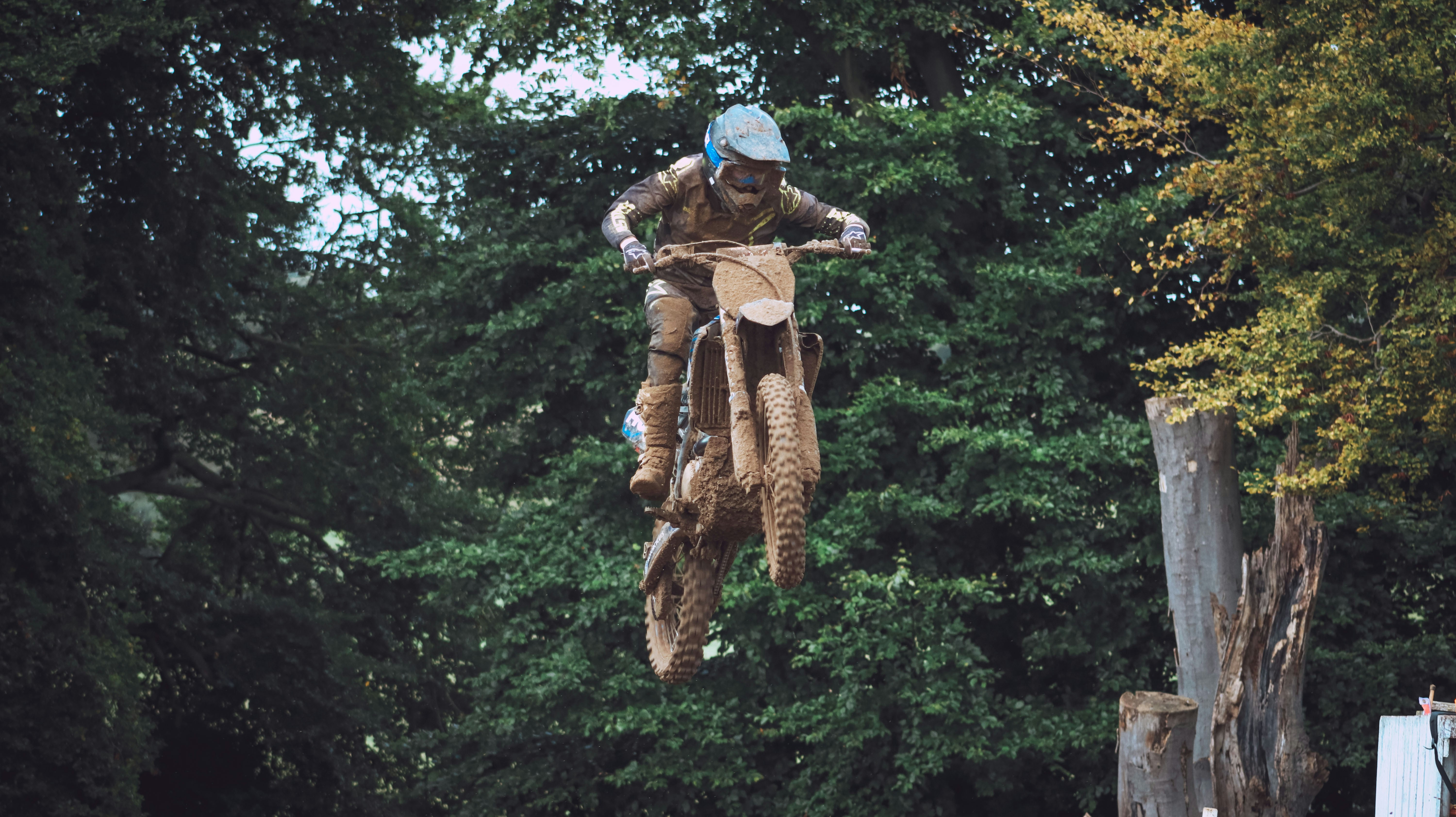 Midair Triumph: Dirt Bike Jump Against a Forest Backdrop