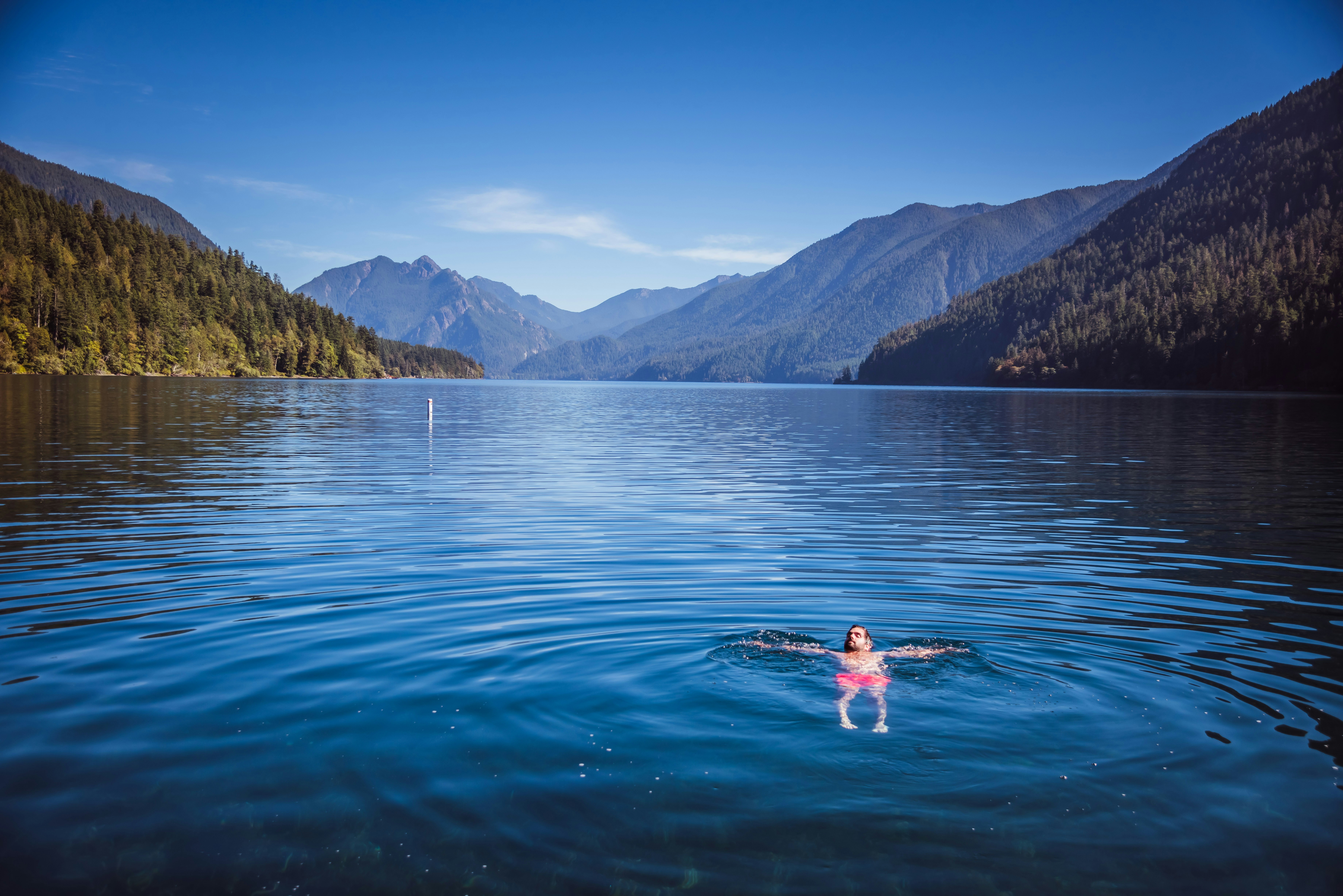a person swimming in a lake with mountains in the background