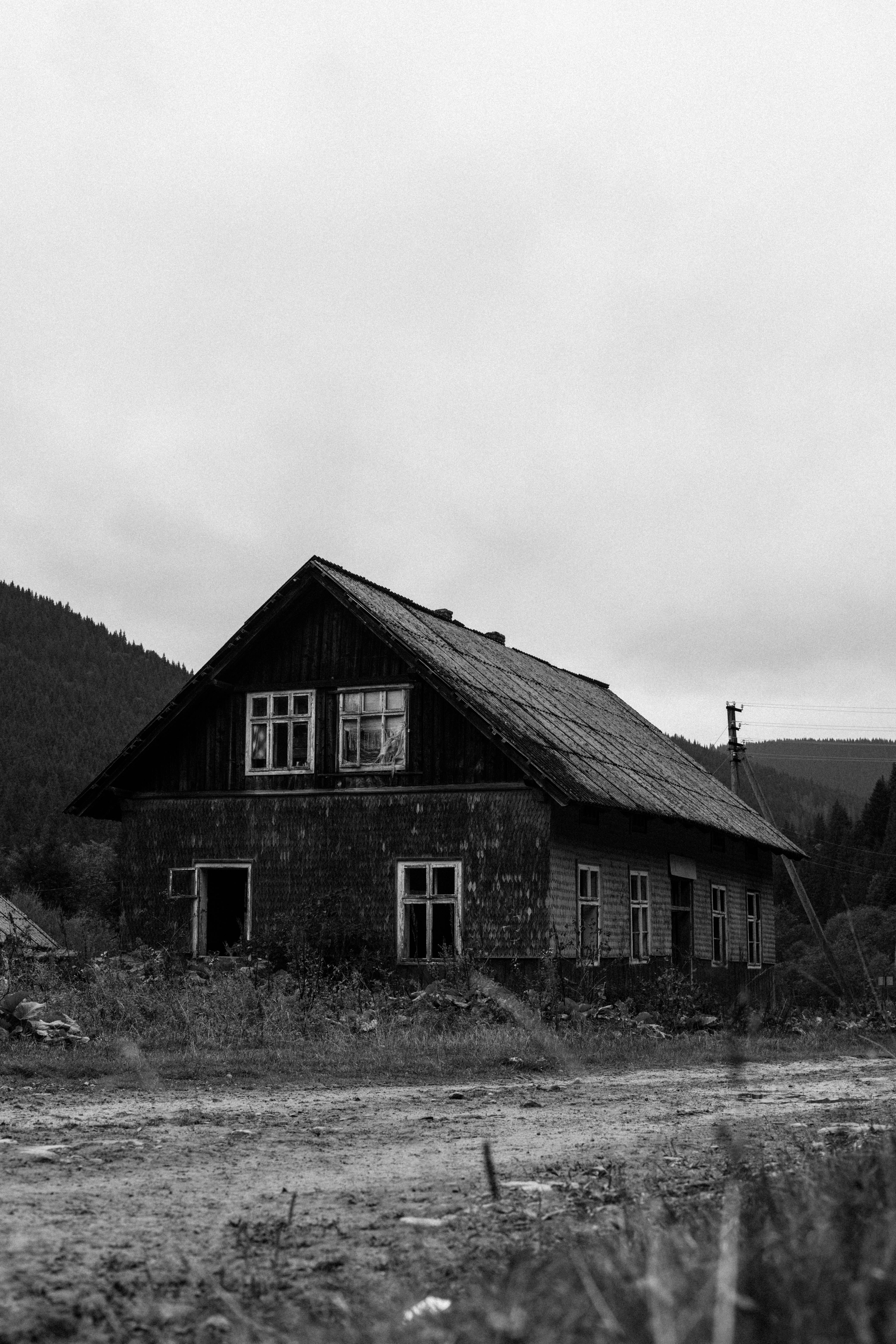 Abandoned wooden house surrounded by overgrown vegetation in a remote landscape, evoking a sense of nostalgia. 
