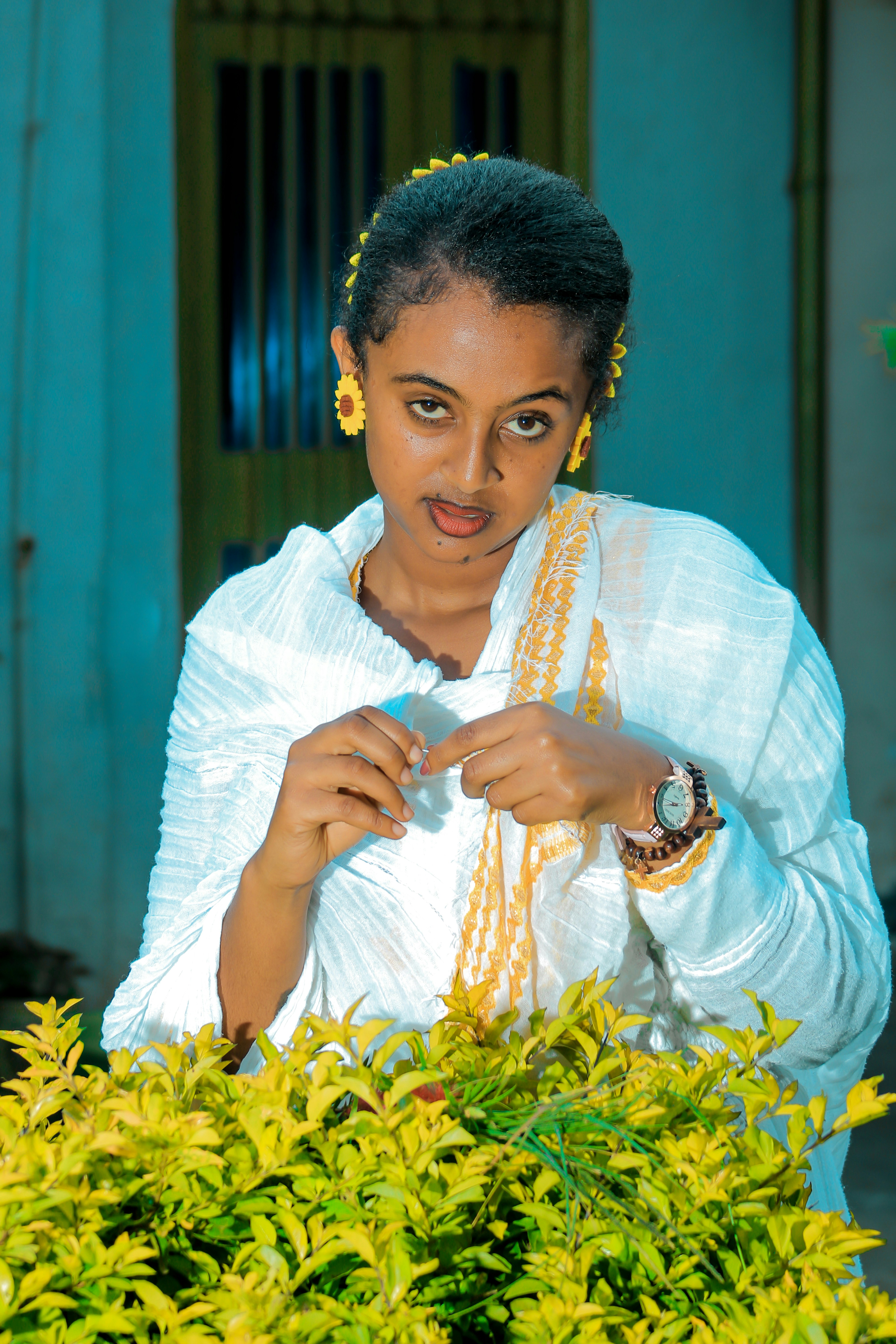 A woman in traditional attire interacts gently with vibrant yellow foliage, embodying a connection between culture and nature.