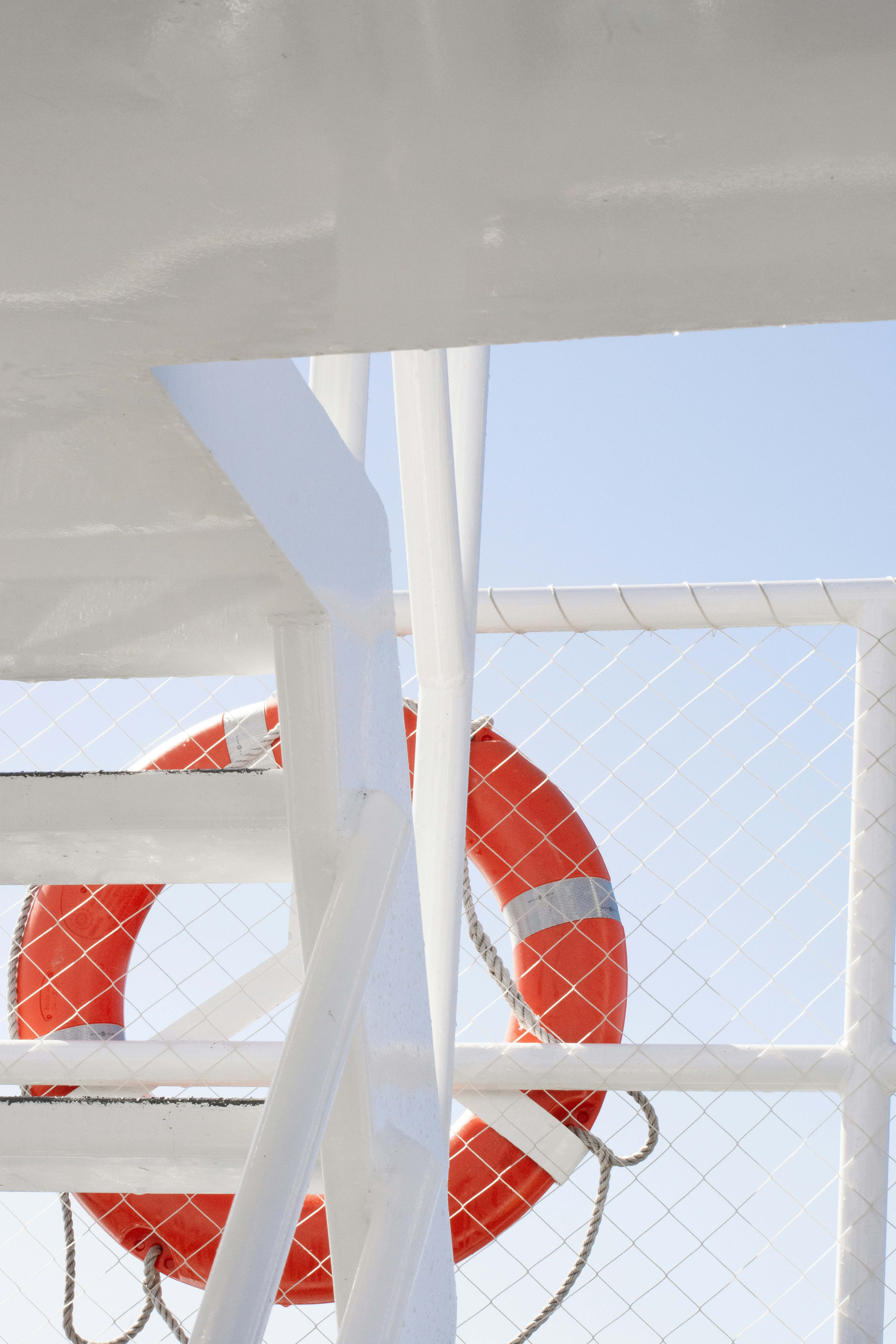 Red Lifebuoy Framed by White Hull and Netting on a Sunny Marine Deck
