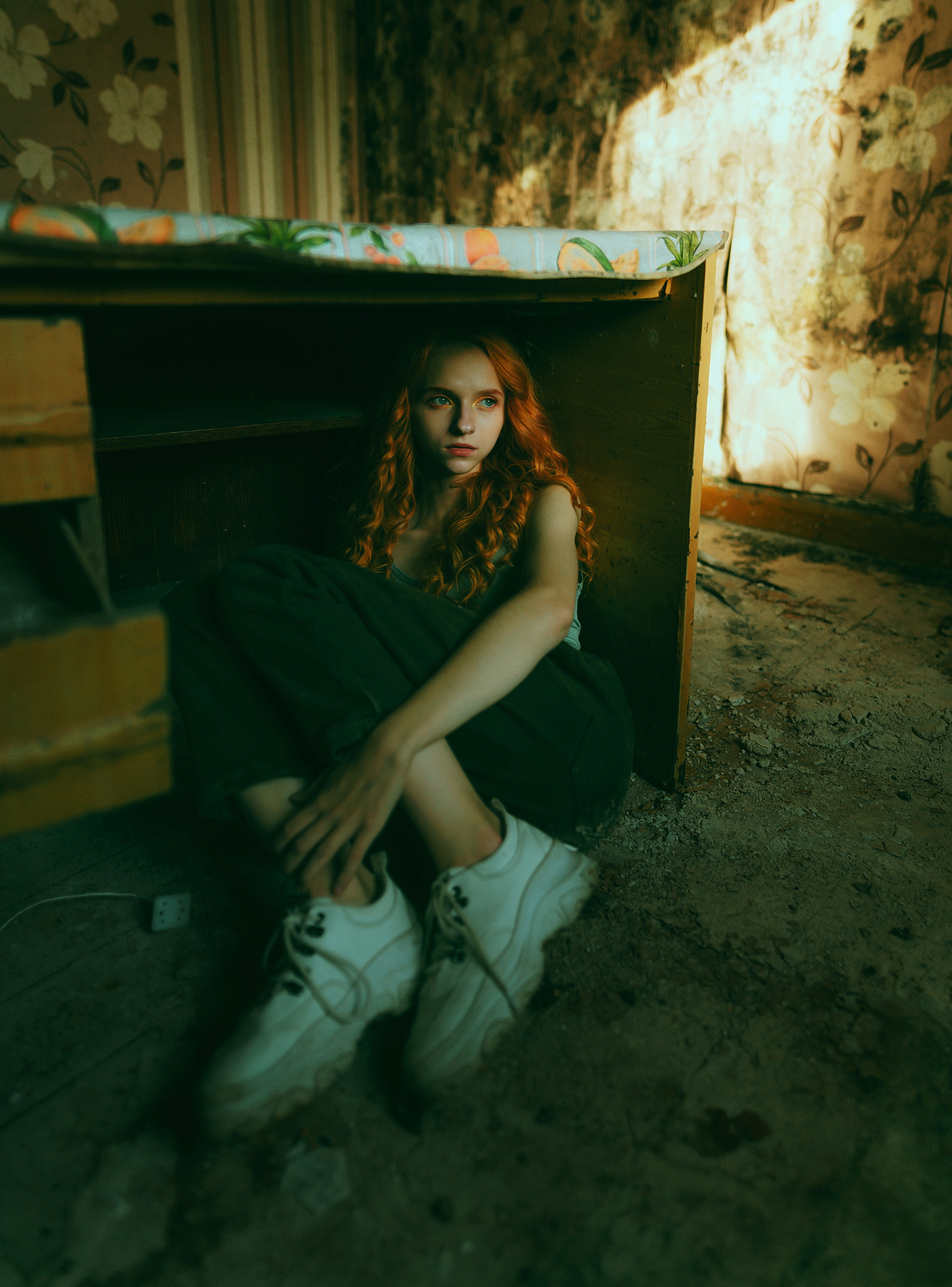 Emerald Glow Beneath the Bed: A Red-Haired Portrait in a Dusty Room