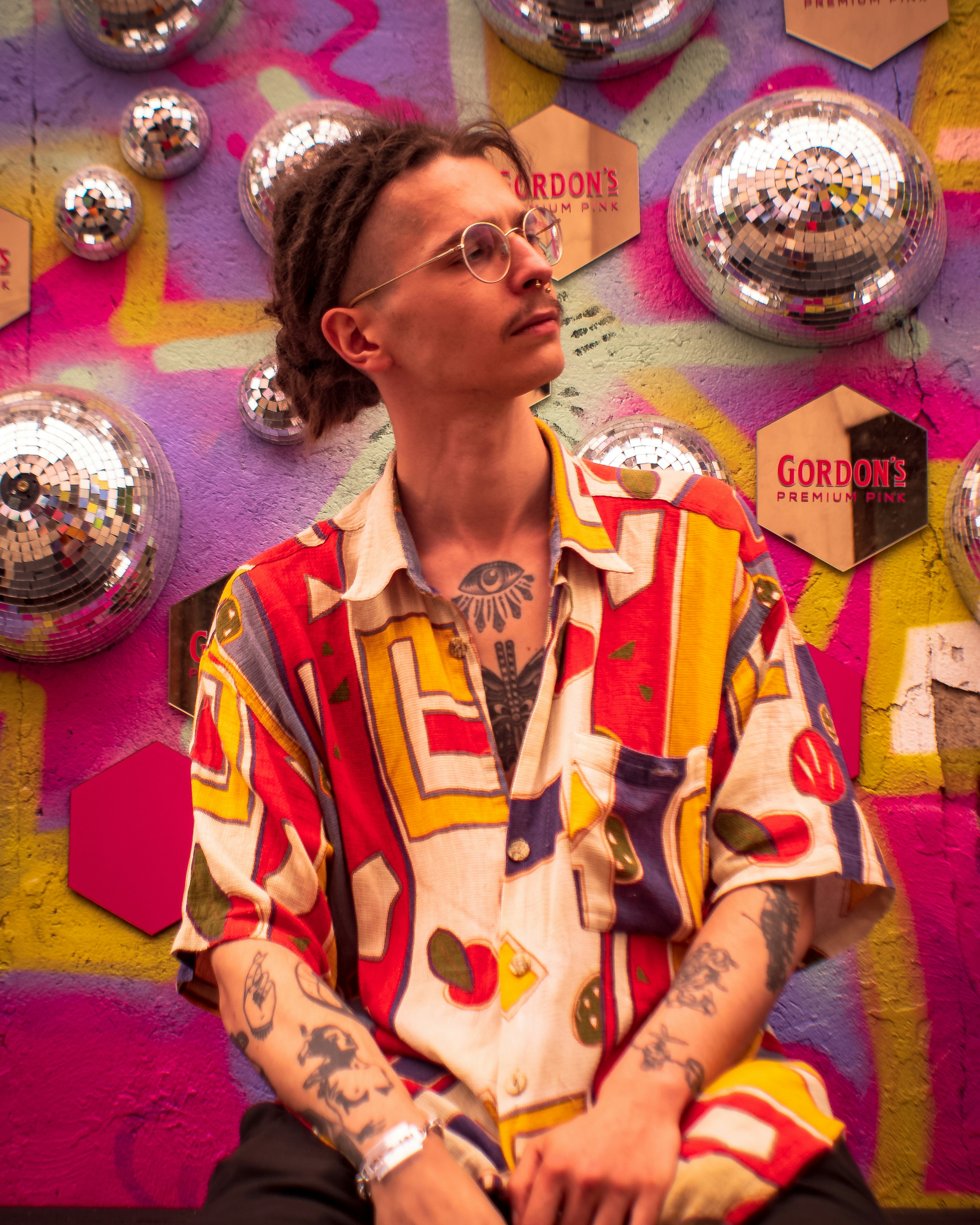 Chromatic Portrait: Tattooed Figure Against a Disco-Graffiti Wall