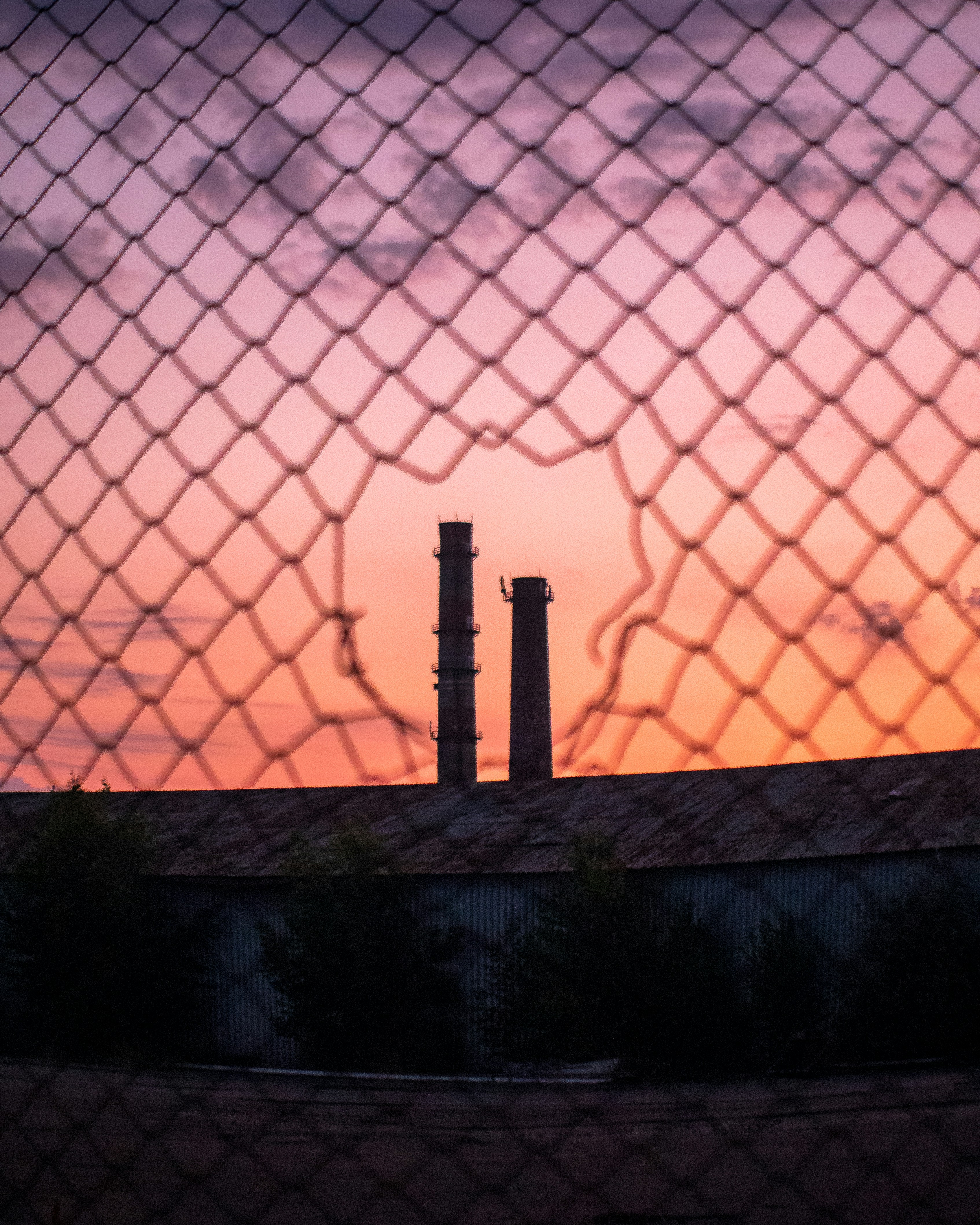 a view of a factory through a mesh fence