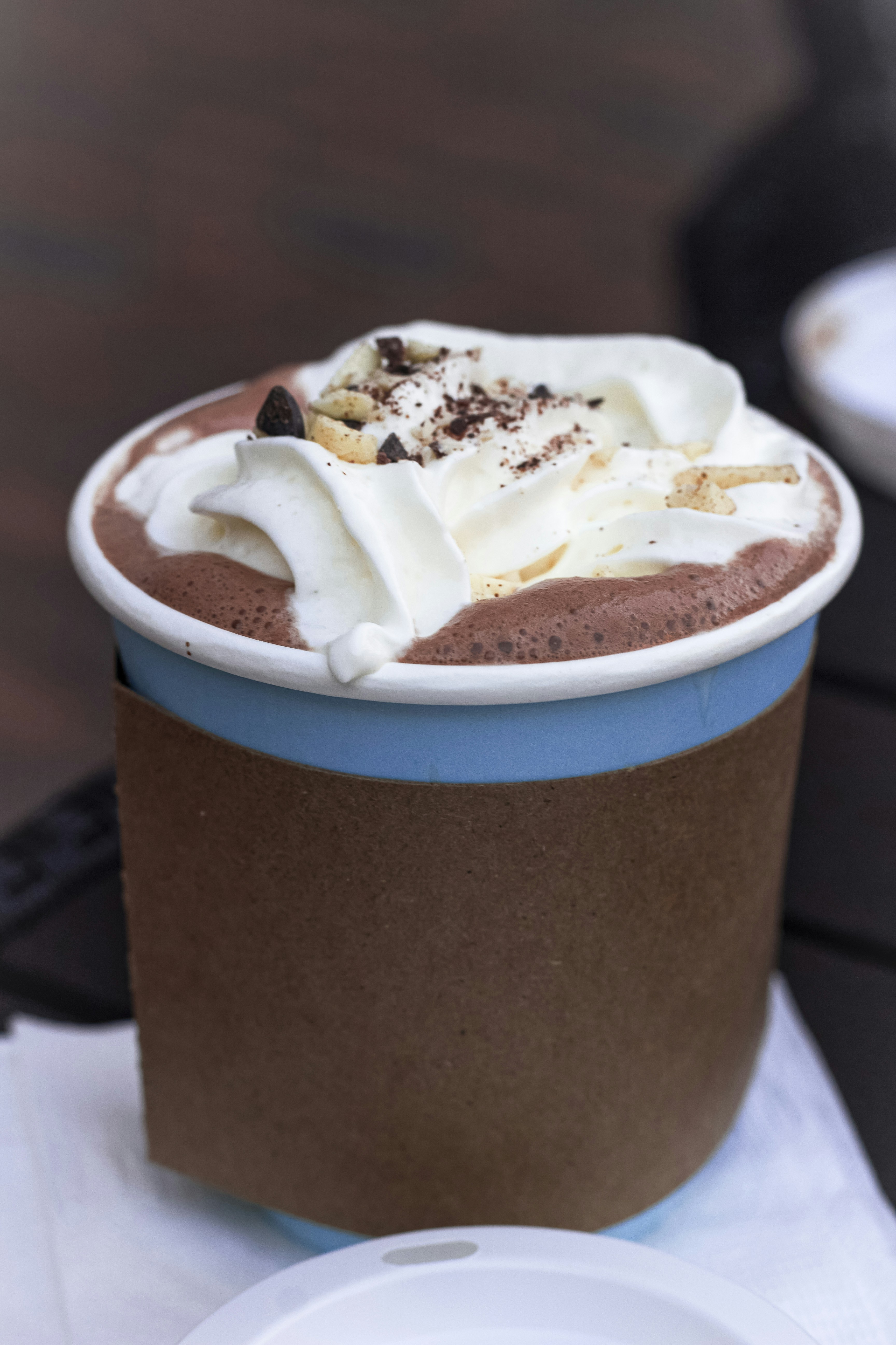 Rich hot chocolate topped with whipped cream and chocolate shavings in a cozy café setting.