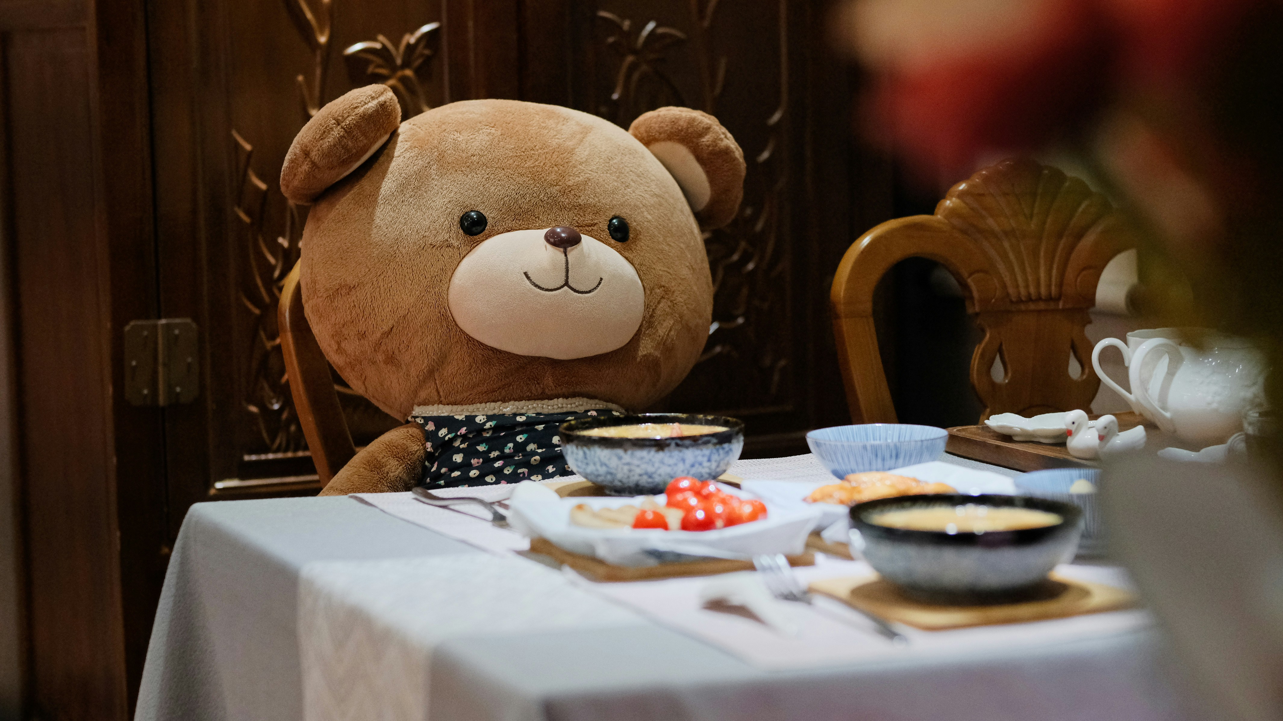 a brown teddy bear sitting at a table with food