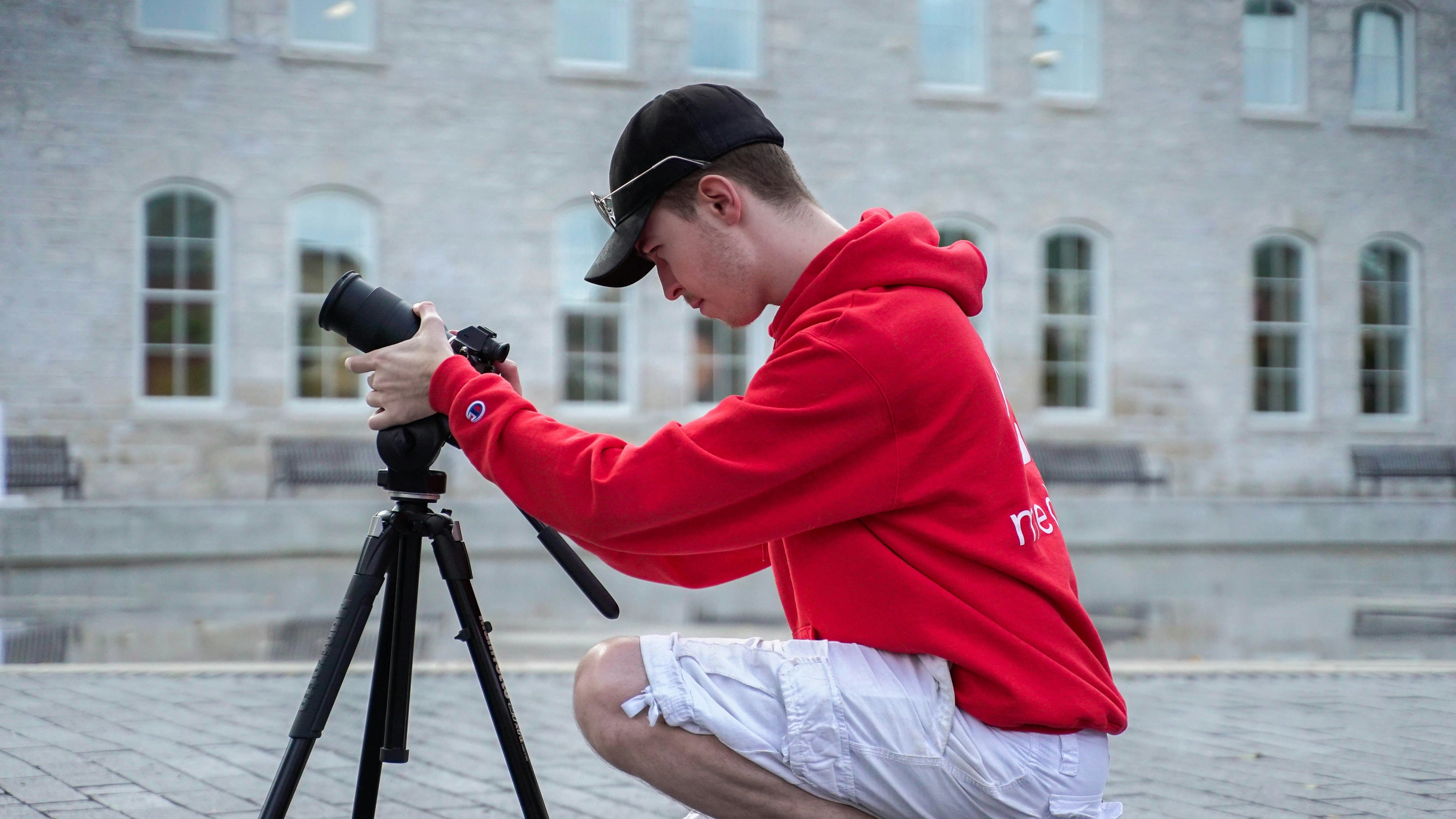 A man squatting down to take a picture with a camera photo – Free ...