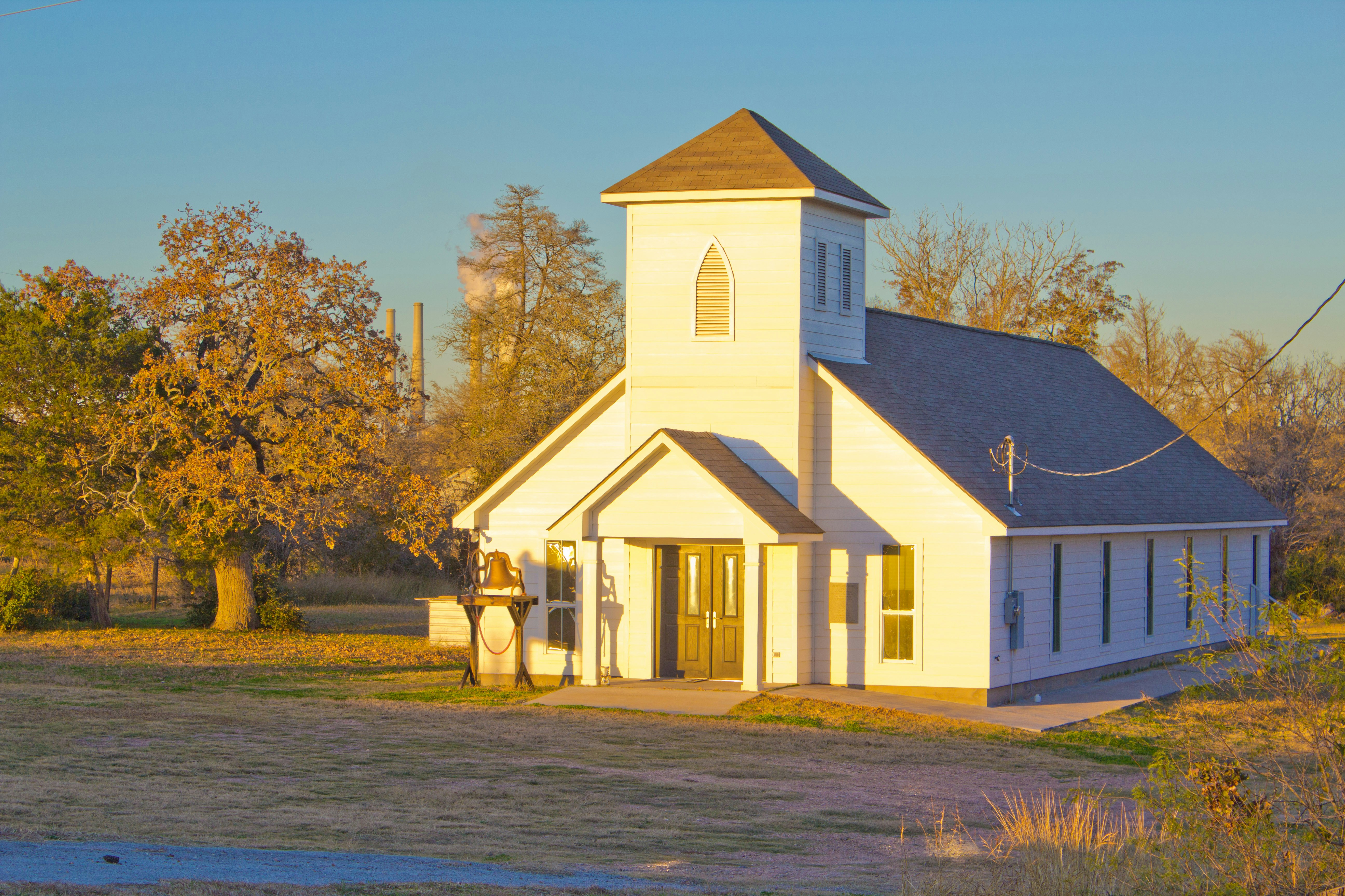 Charming white chapel with a steeple surrounded by autumn foliage, set against a clear sky. The scene captures the essence of community and tranquility.