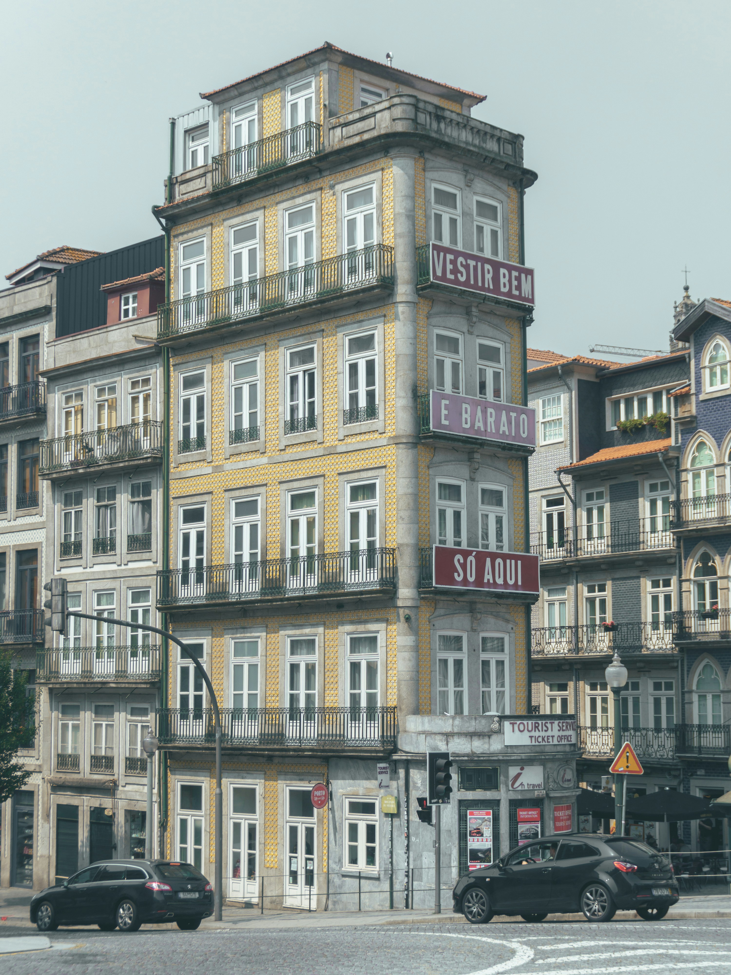 Historic yellow building with large windows and prominent signage in a bustling urban setting. The architecture reflects a blend of modern and traditional styles.