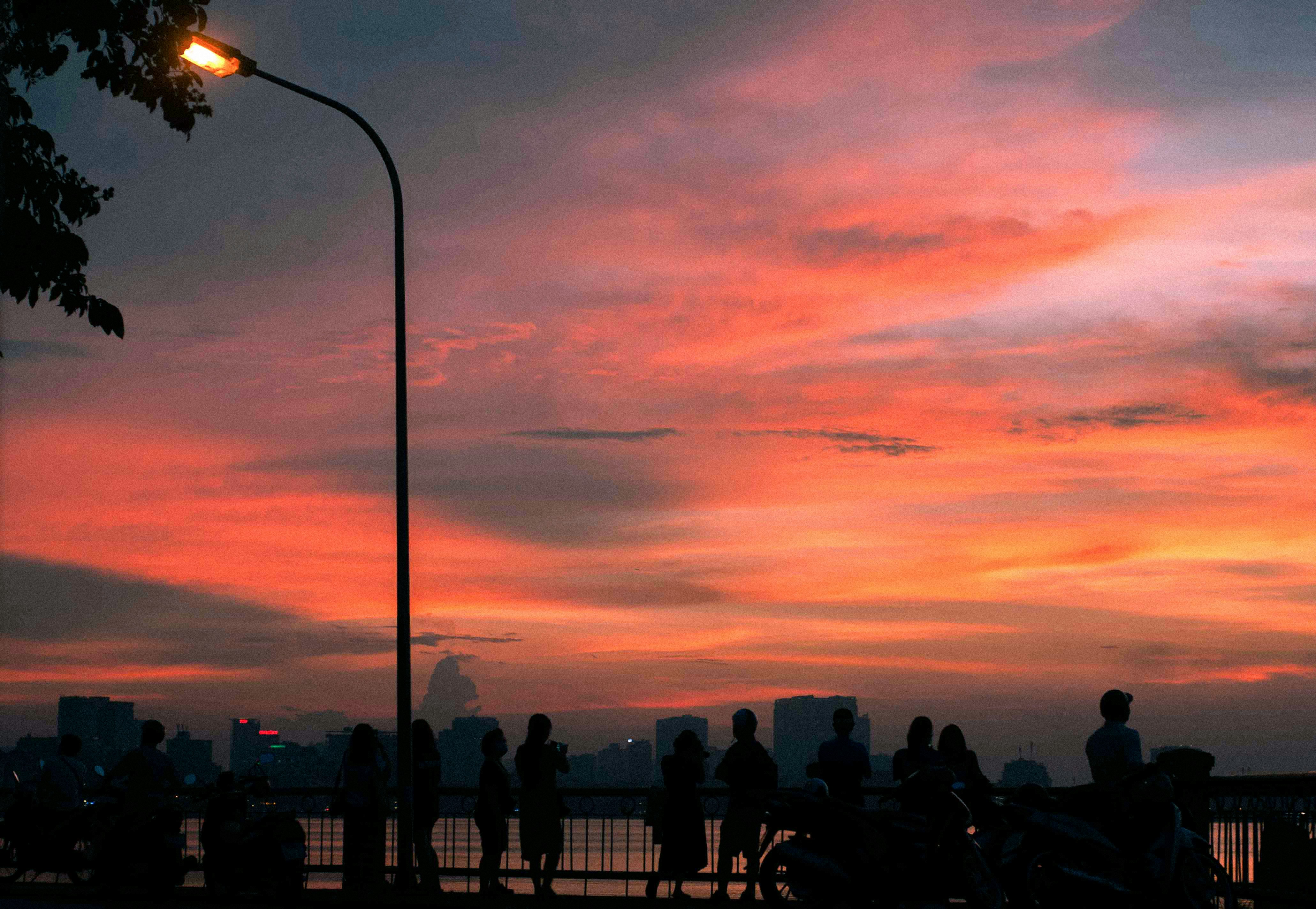 Riverside Dusk: silhouettes along the railing beneath a molten sunset