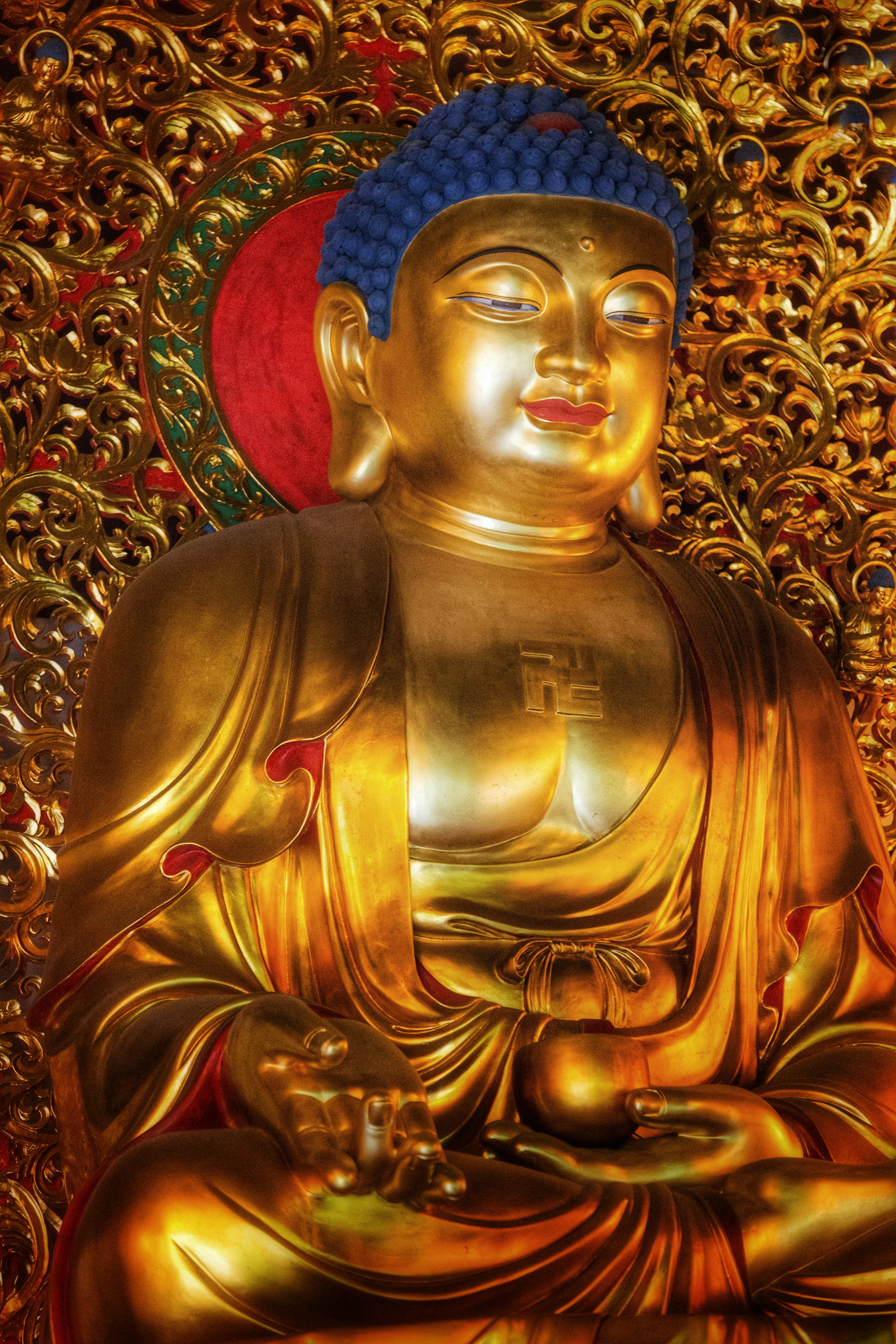 A majestic golden Buddha statue adorned with intricate designs and vibrant colors, set against a richly detailed background. The serene expression invites contemplation.