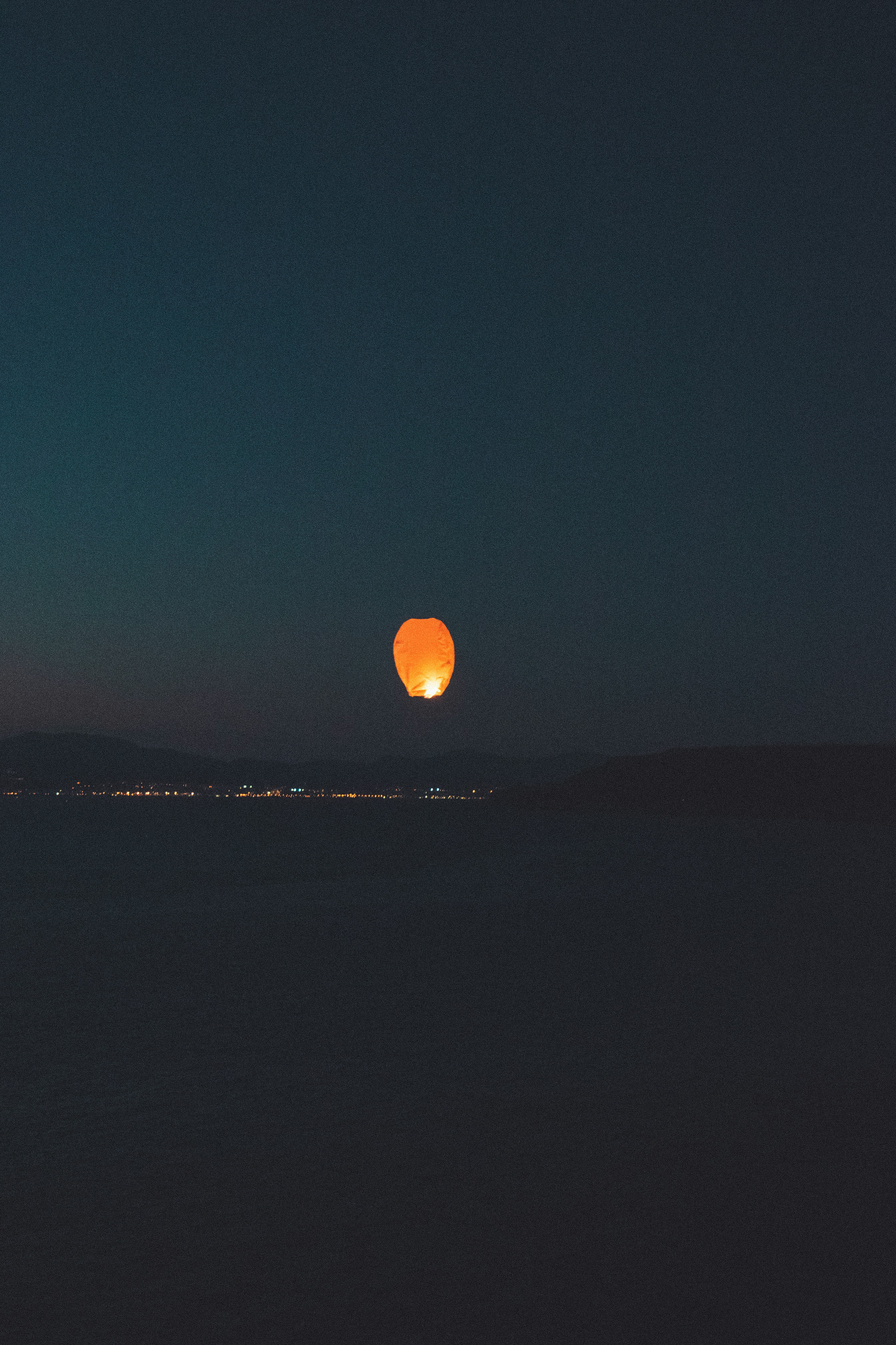 Floating lantern over a quiet night shoreline