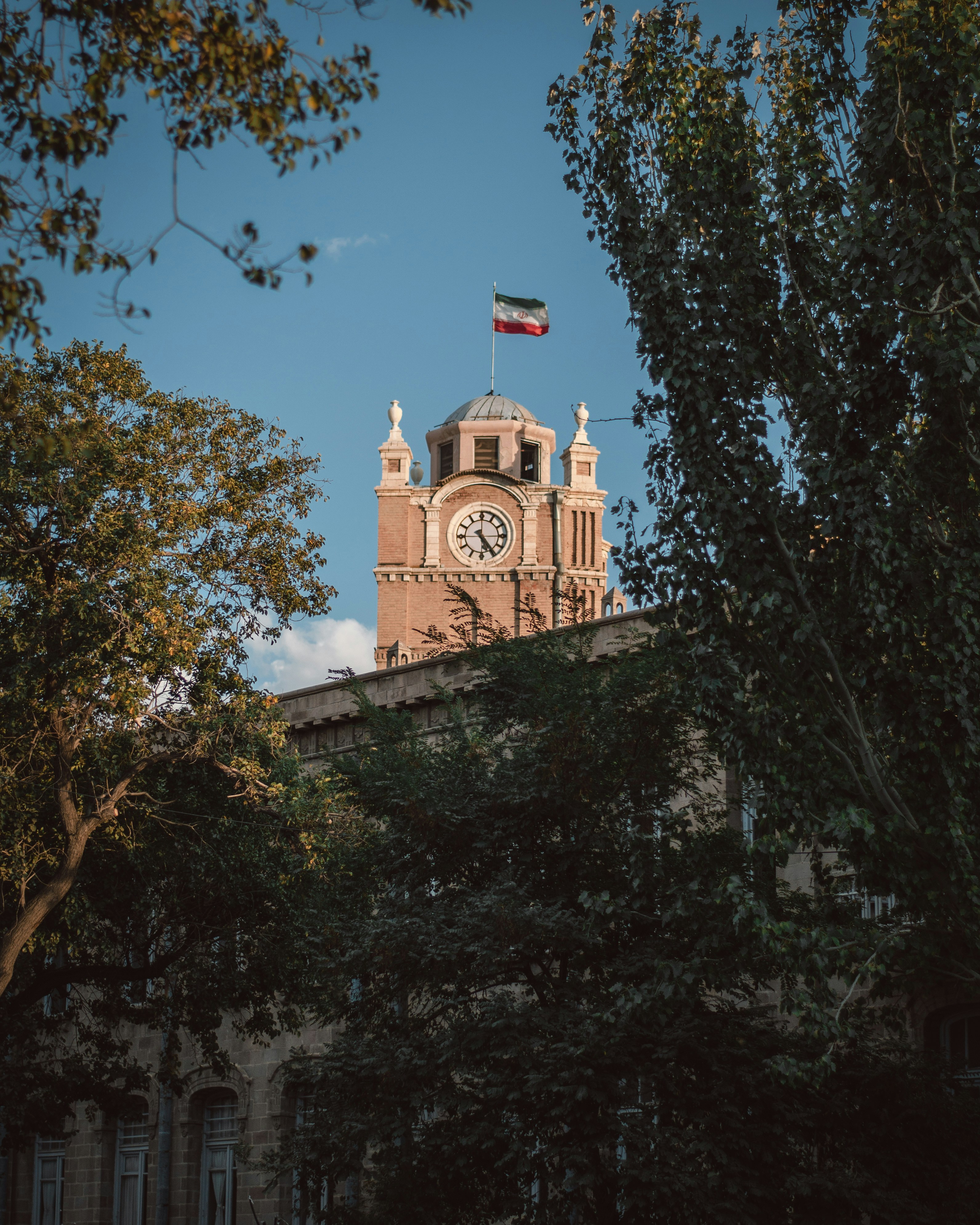 A clock tower with a flag on top of it photo – Free Tabriz Image on ...
