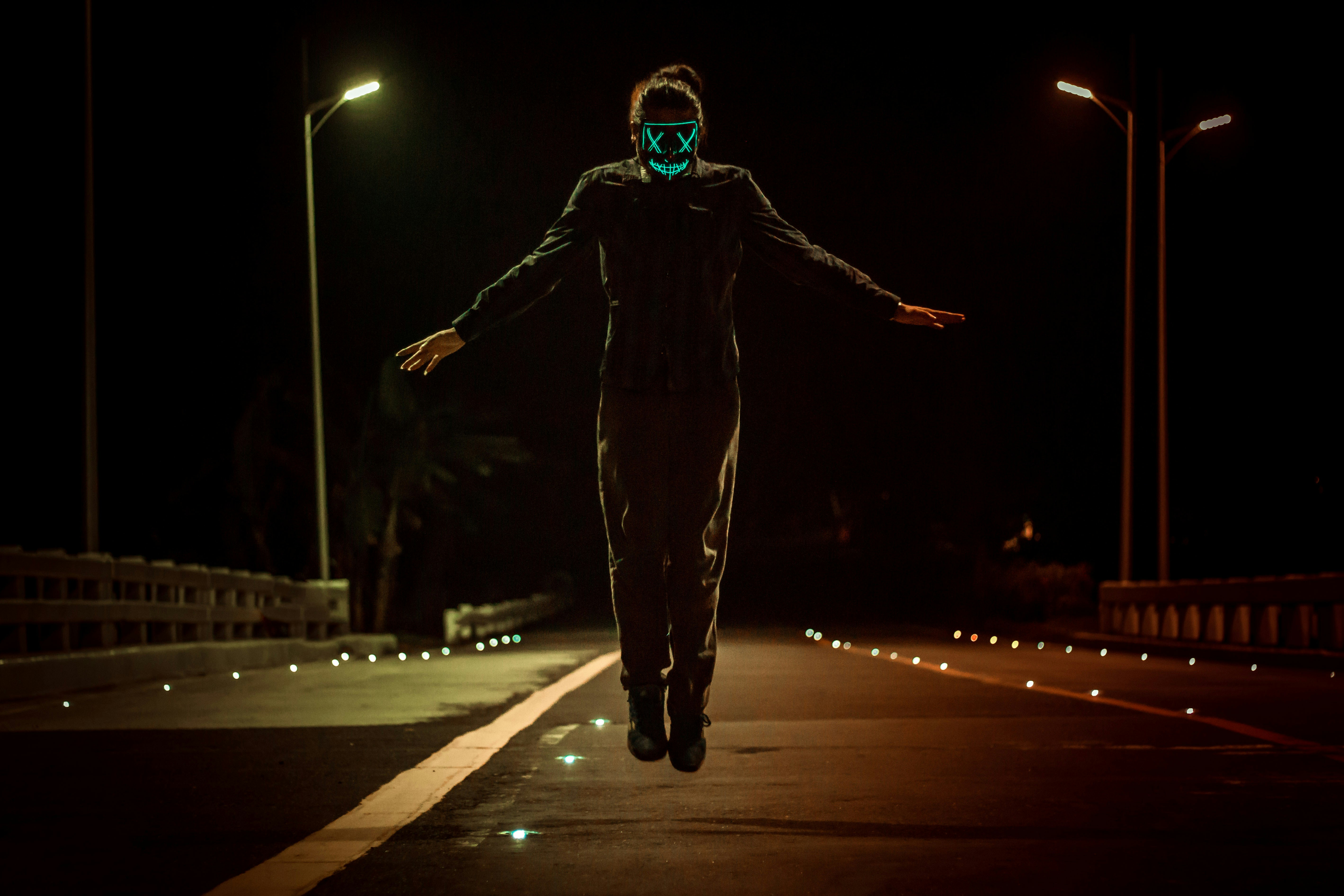 A man wearing a mask and goggles running down a street at night photo ...