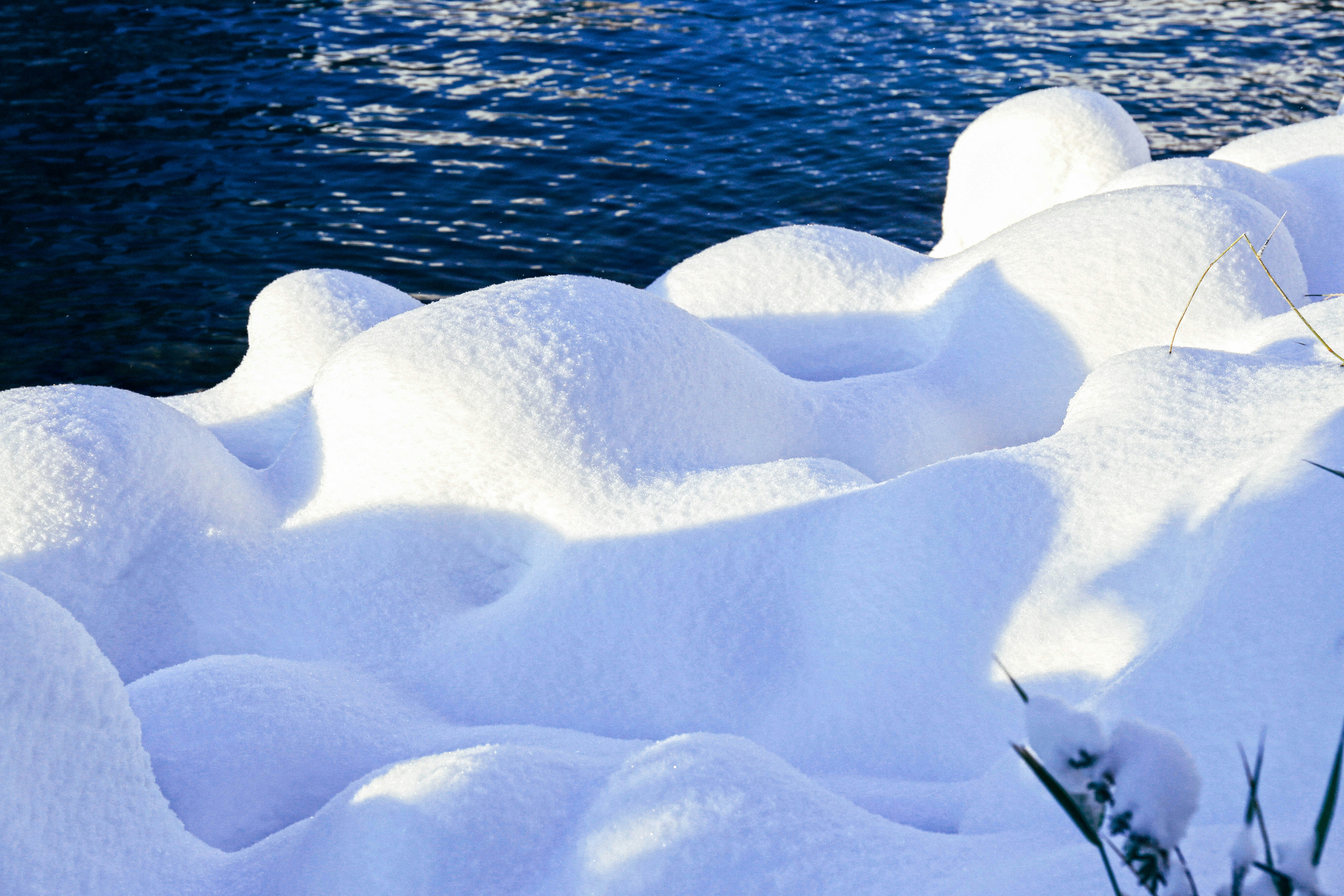 A bunch of snow that is next to a body of water photo – Free Blue Image ...