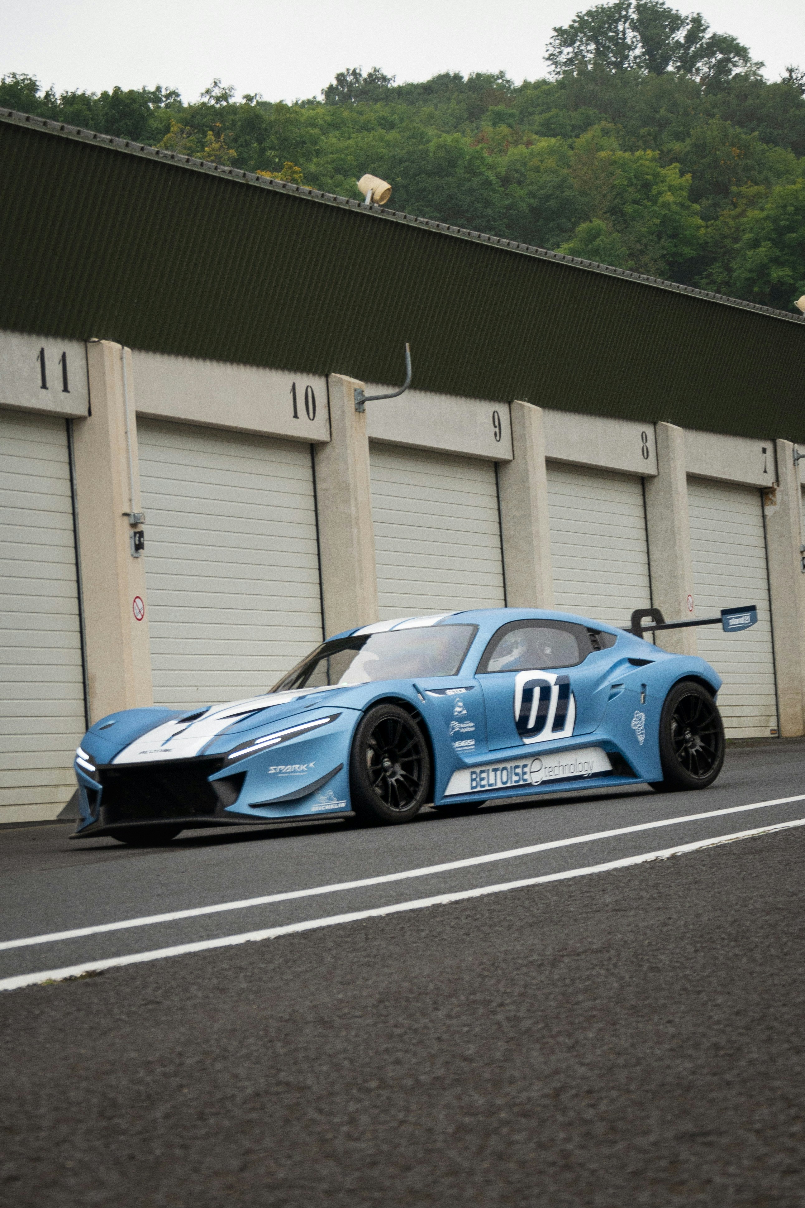 A blue sports car driving down a race track photo – Free Circuit de ...
