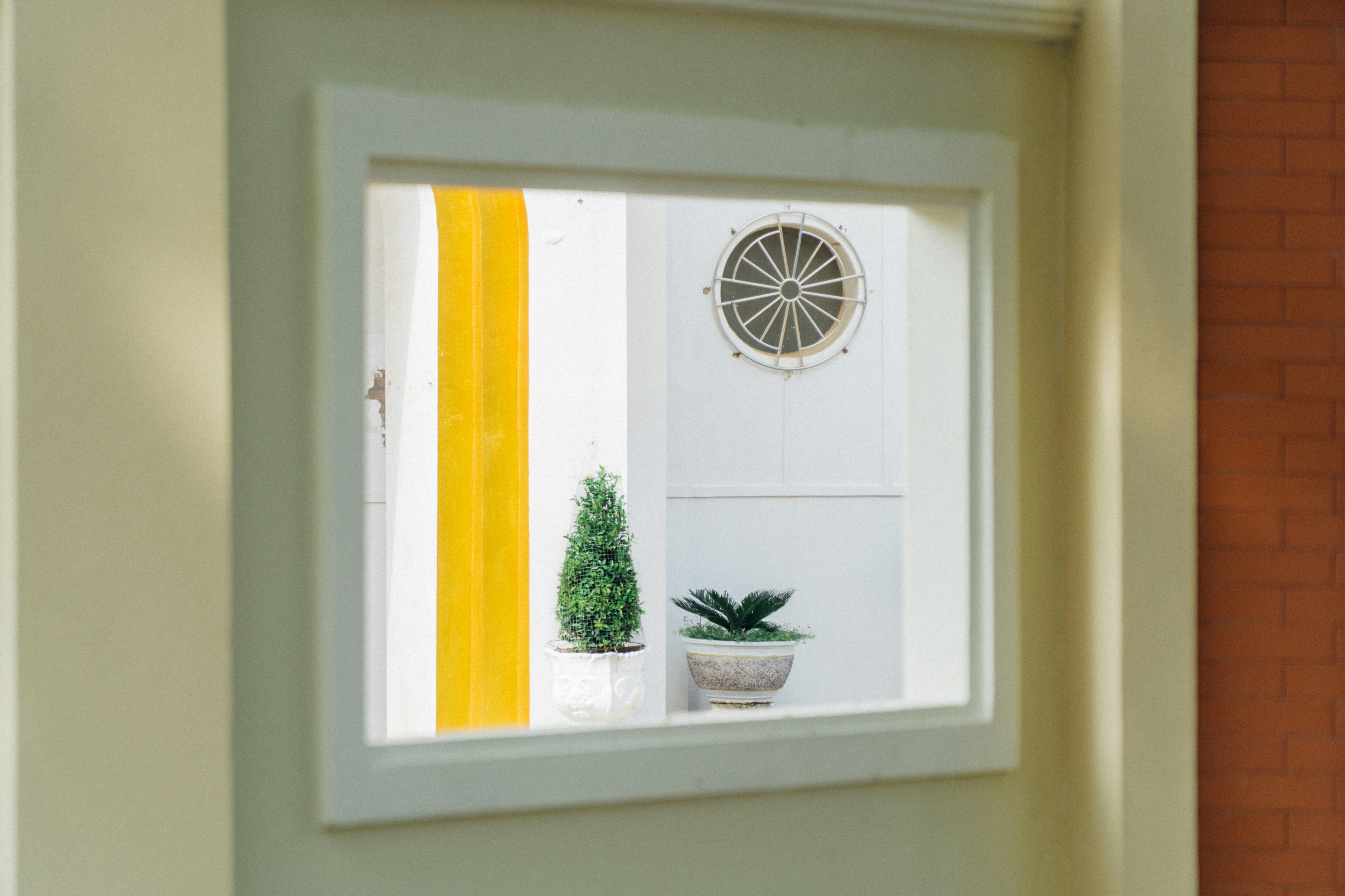 Windowed Alcove: Yellow Pillar and Twin Pots Framed by a Circular Vent