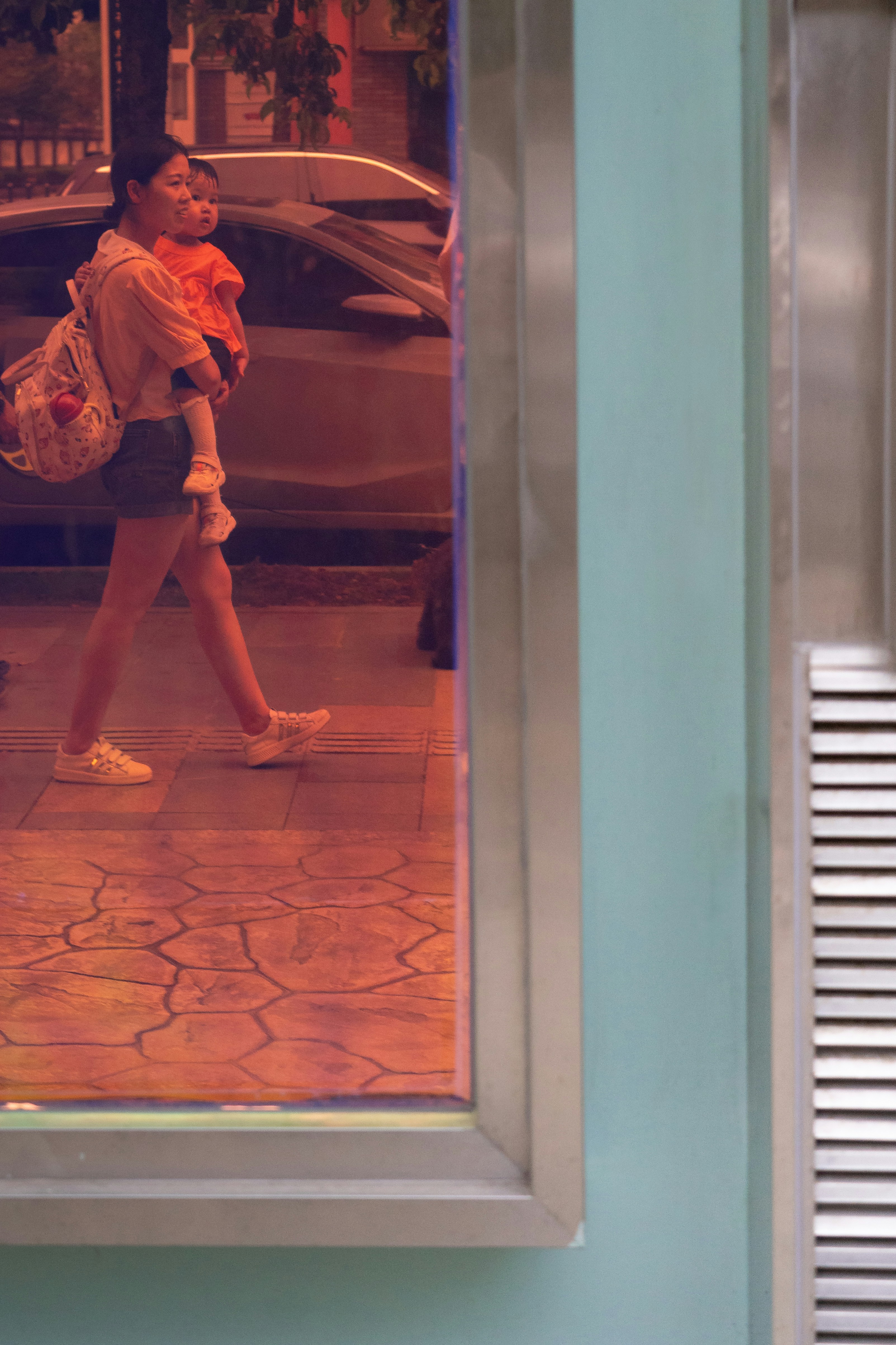 Pedestrian in Transit: A mother and child in a storefront reflection