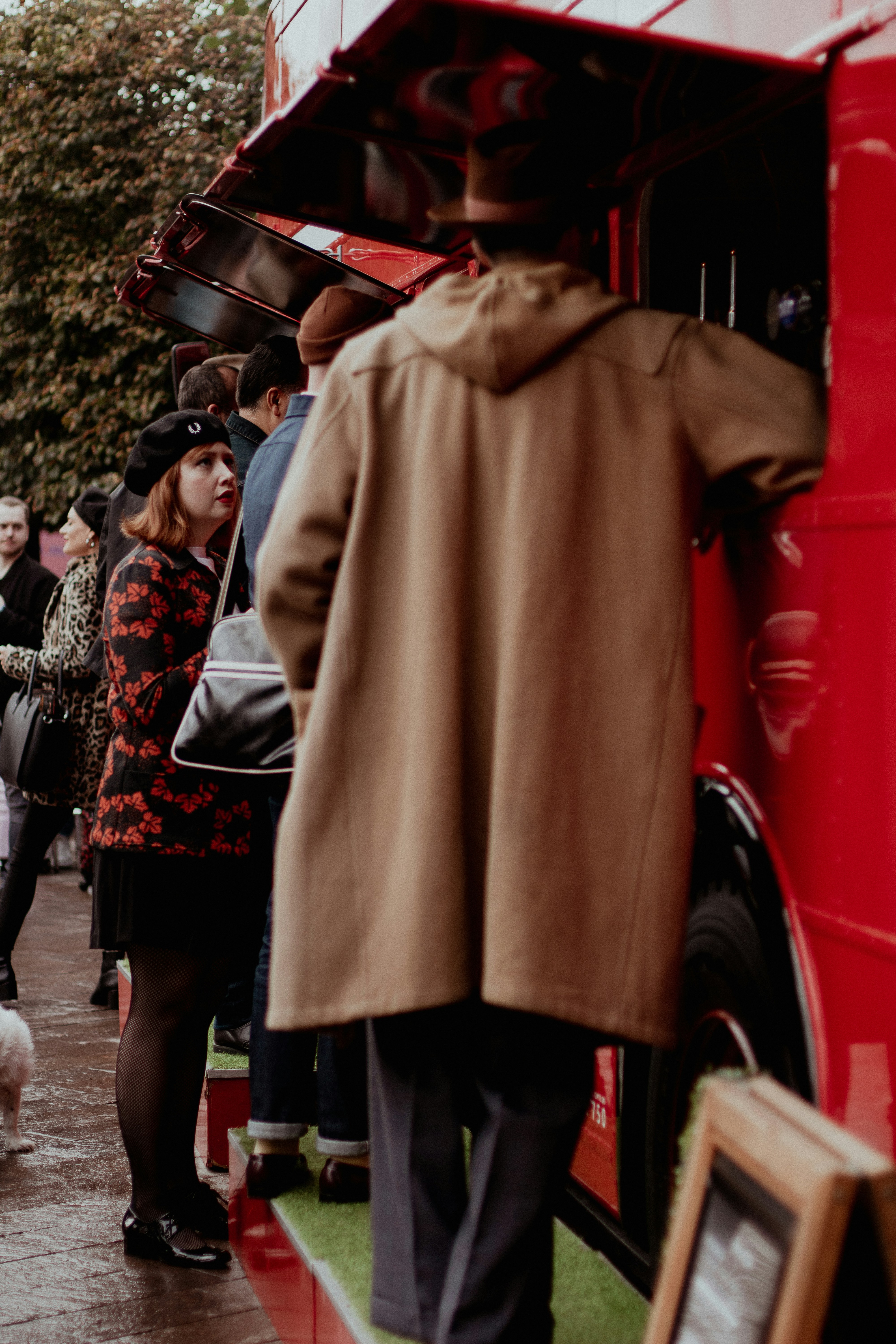 A bustling scene at a food truck, featuring a diverse crowd engaged in conversation and enjoying the atmosphere. The vibrant red truck adds a retro charm to the lively setting.