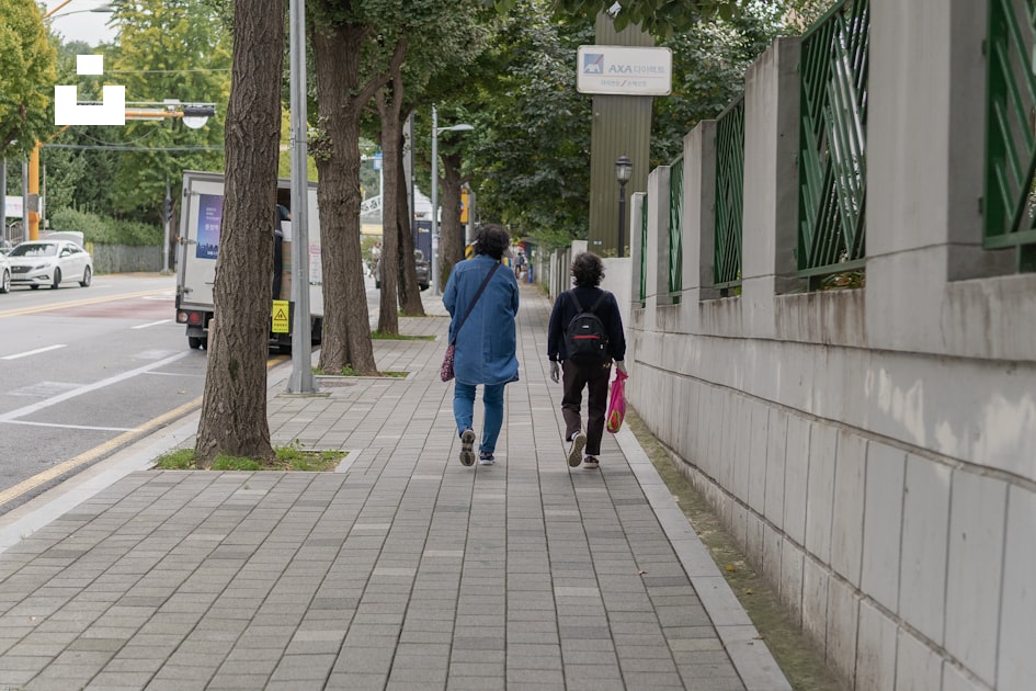 나무 옆 보도를 걷고 있는 두 사람 사진 Unsplash의 무료 걷기 이미지