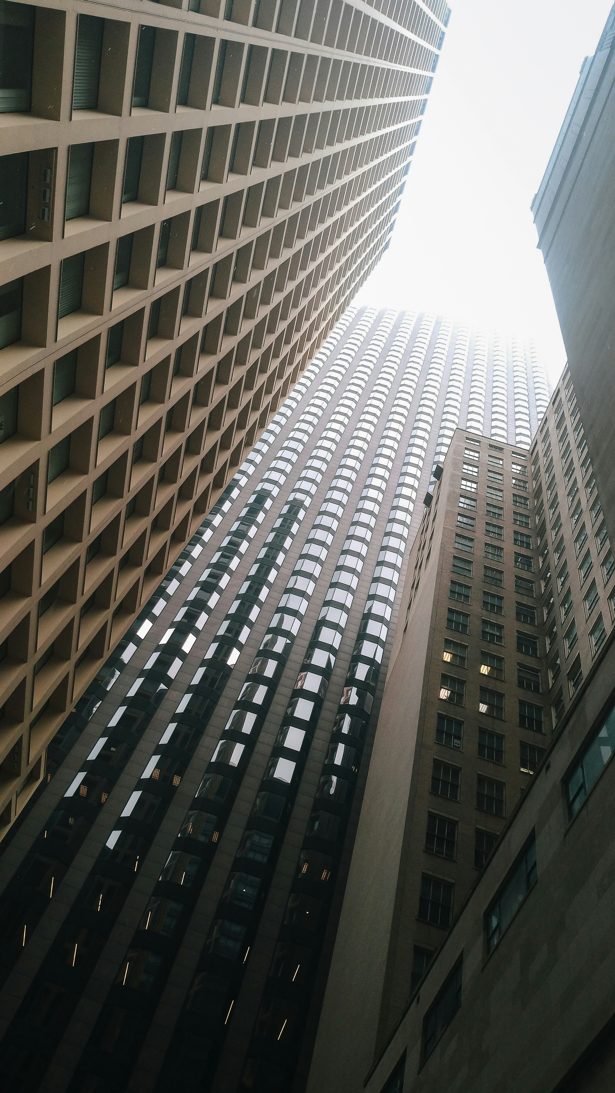 A dramatic view looking up between towering skyscrapers, showcasing the interplay of light and shadow in an urban canyon.