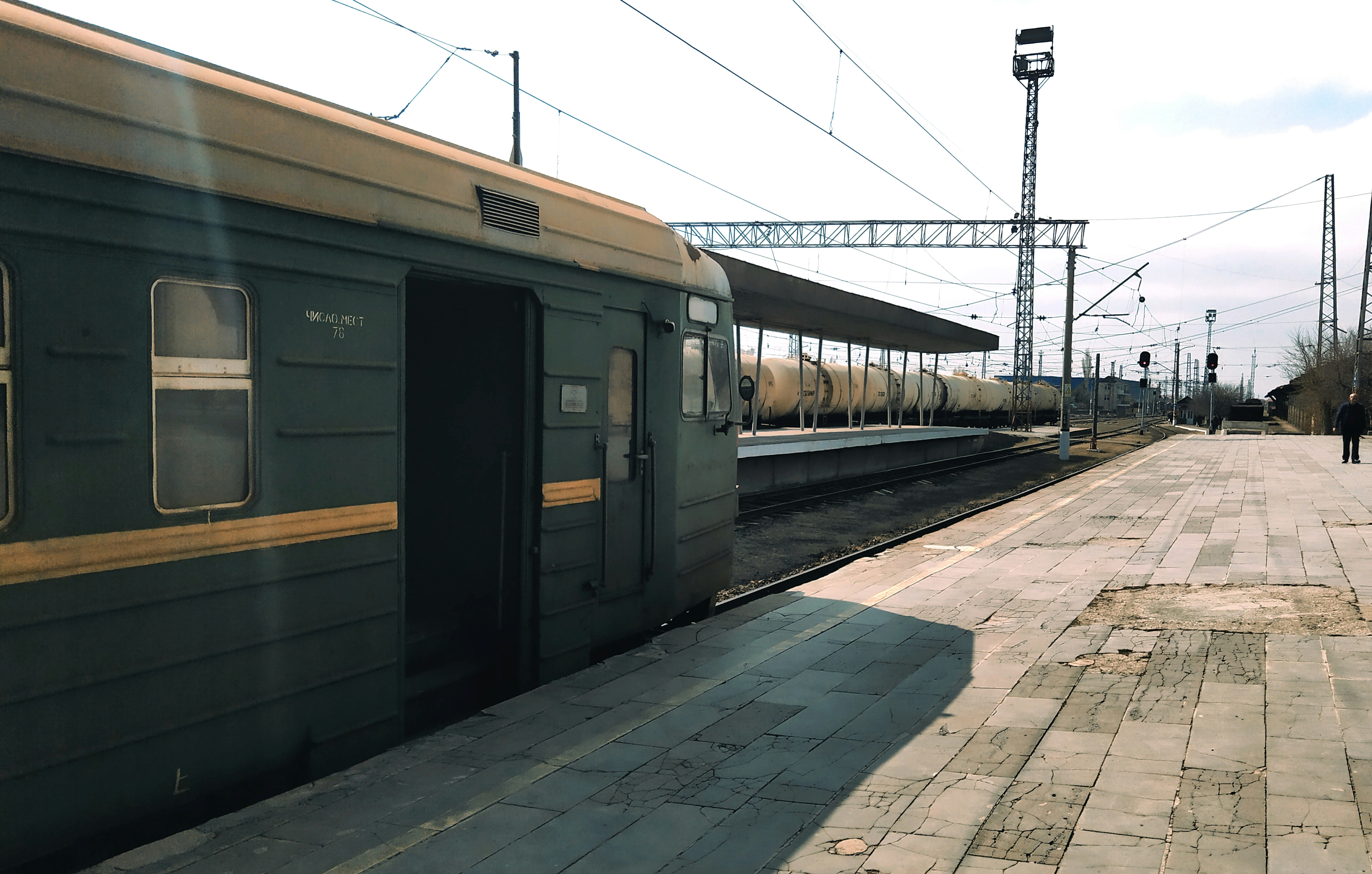 A vintage train car sits idle at an empty platform under a cloudy sky in Gyumri, Armenia.