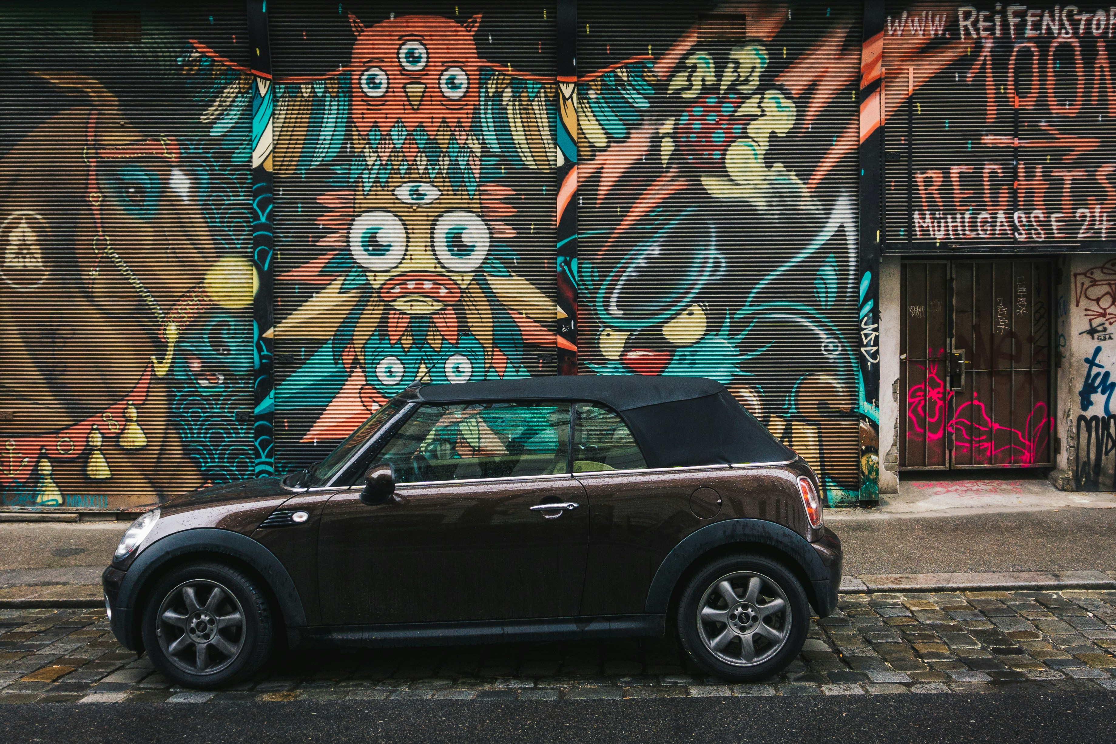 Urban Chrome: A Black Convertible Stopped Before a Graffiti Echo
