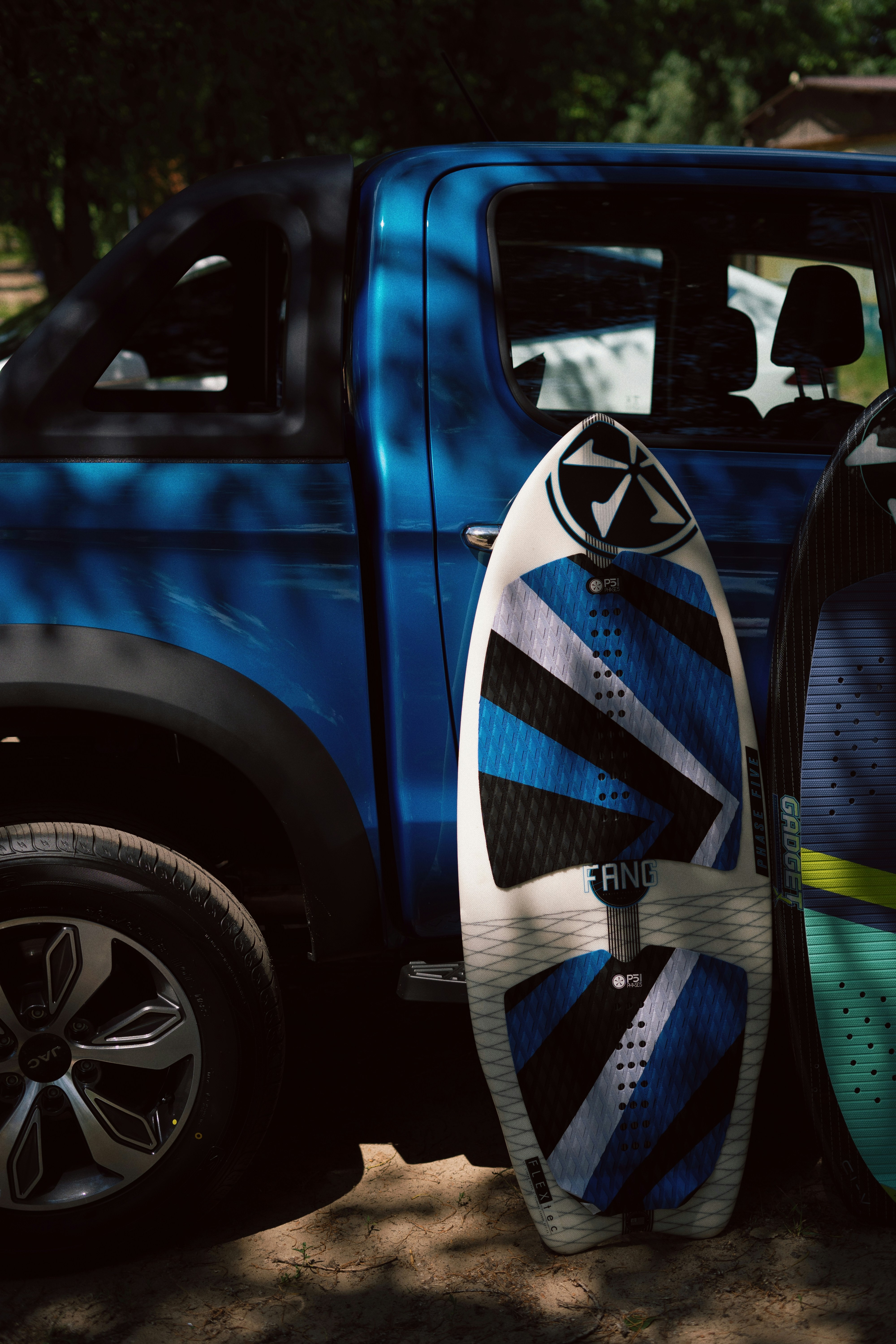 two surfboards are propped up against a blue truck